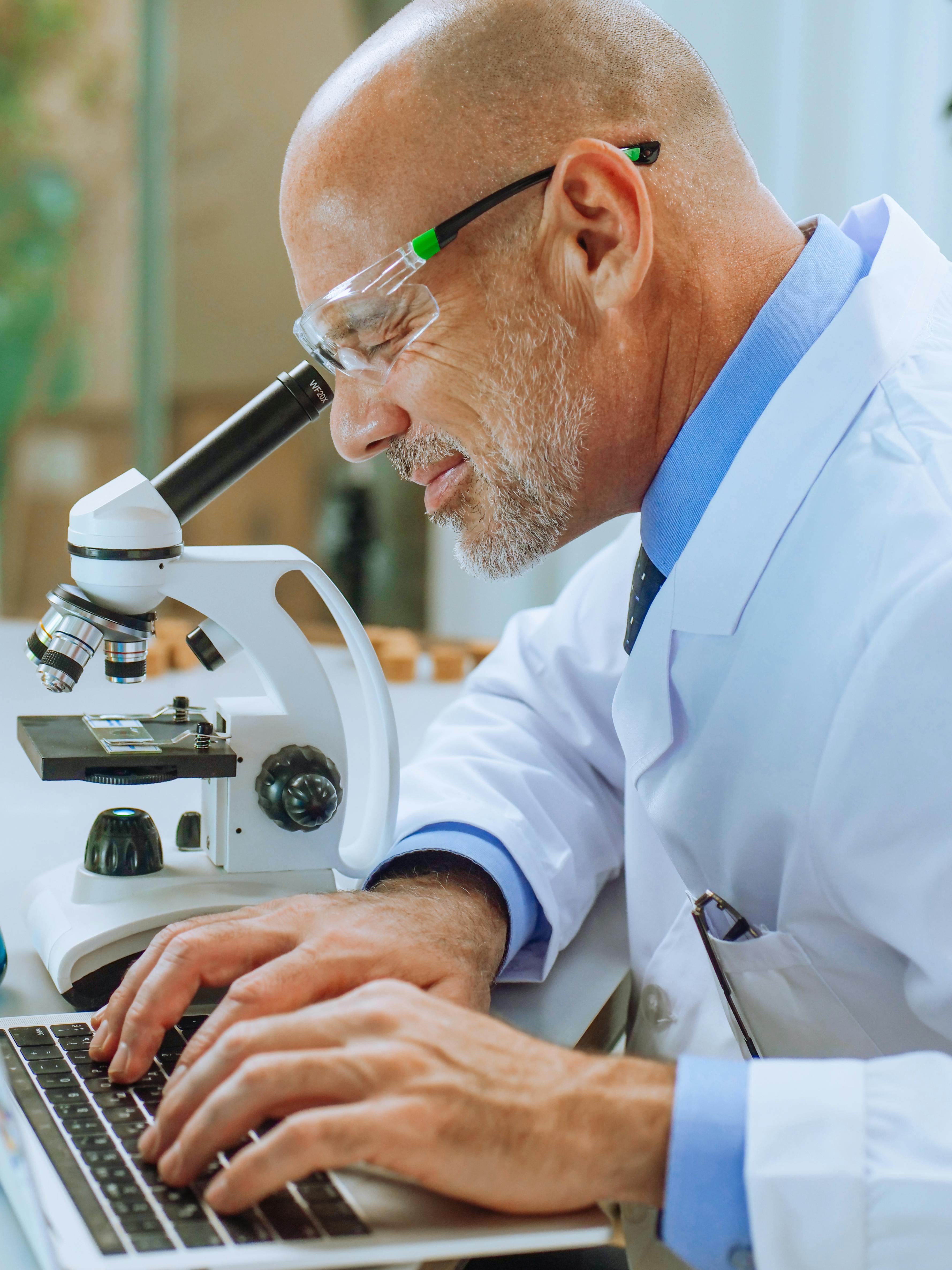 A Man Examining a Microscope Slide · Free Stock Photo