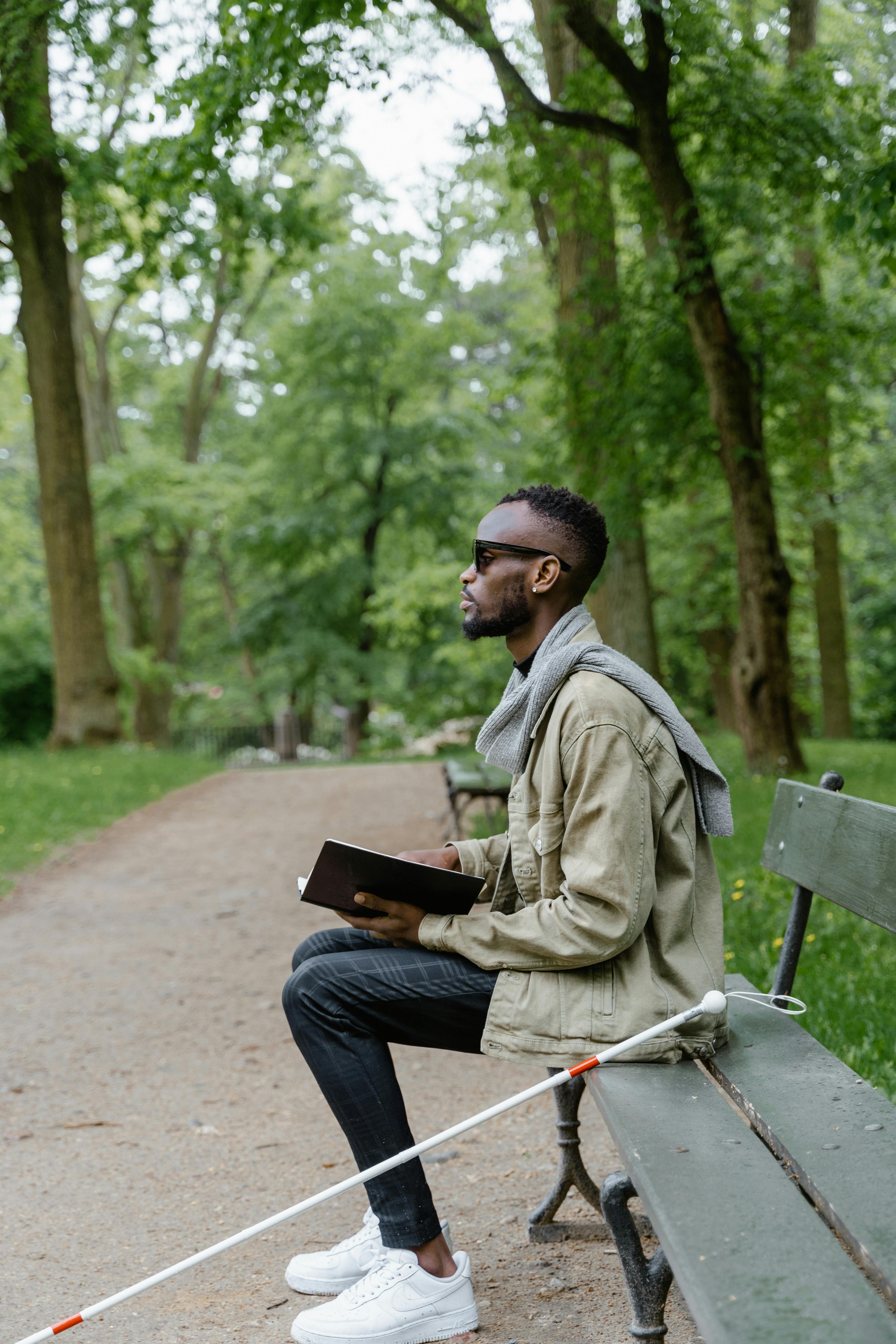 Man Sitting on Bench While Holding a Book · Free Stock Photo