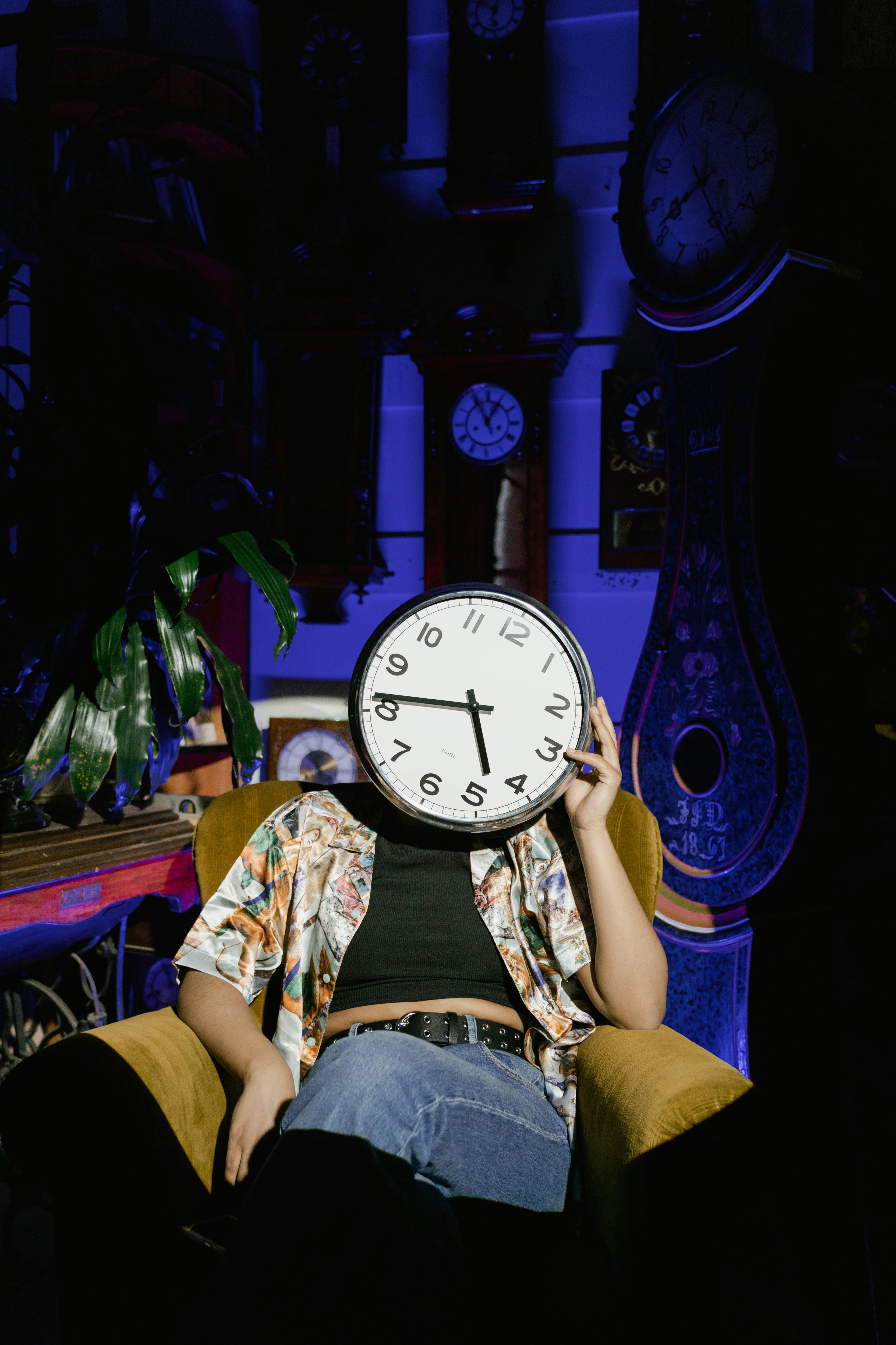 A Person Sitting on a Couch while Covering His Head Using Wall Clock ...