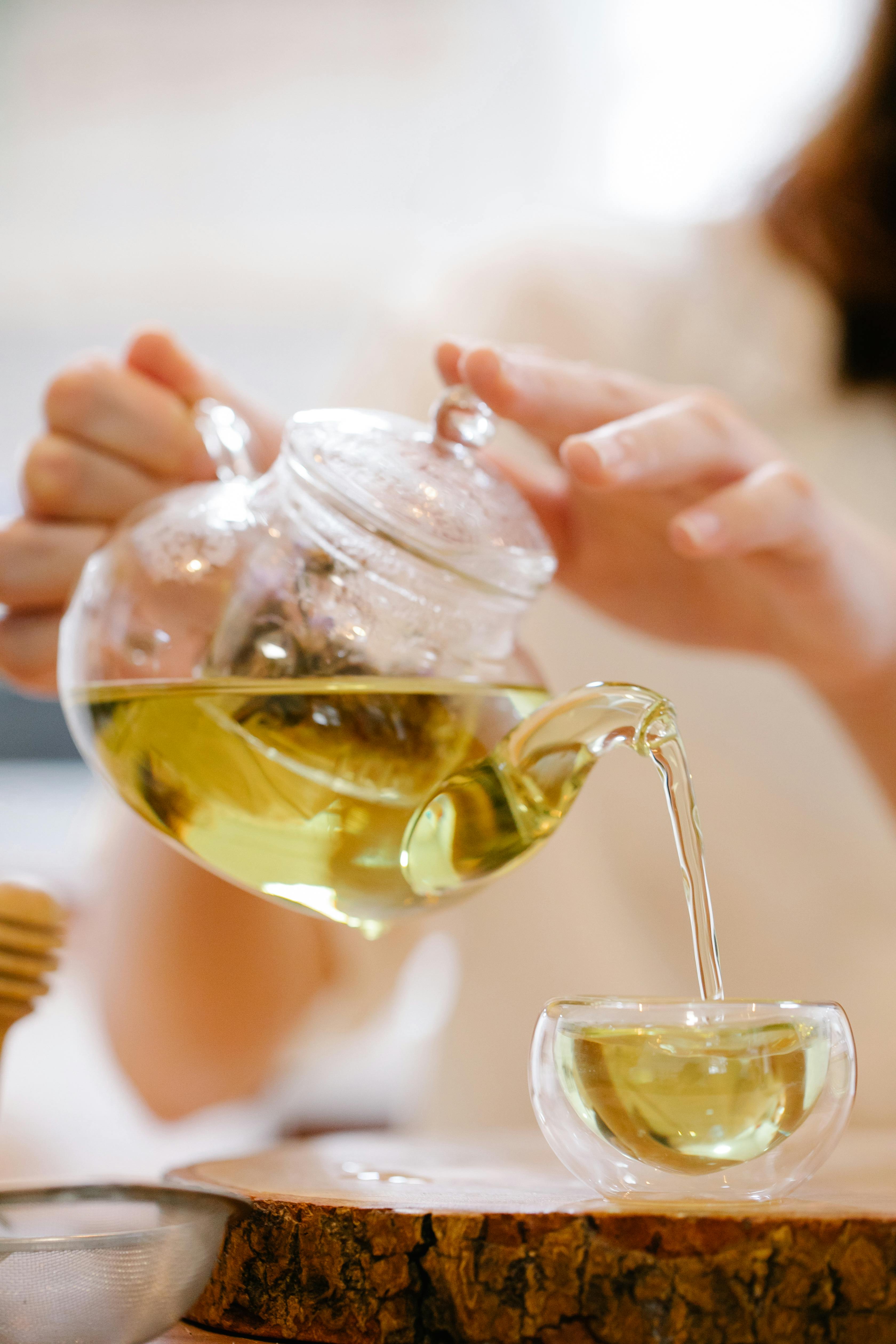 Close-up of Woman Pouring Tea from a Glass Teapot · Free Stock Photo