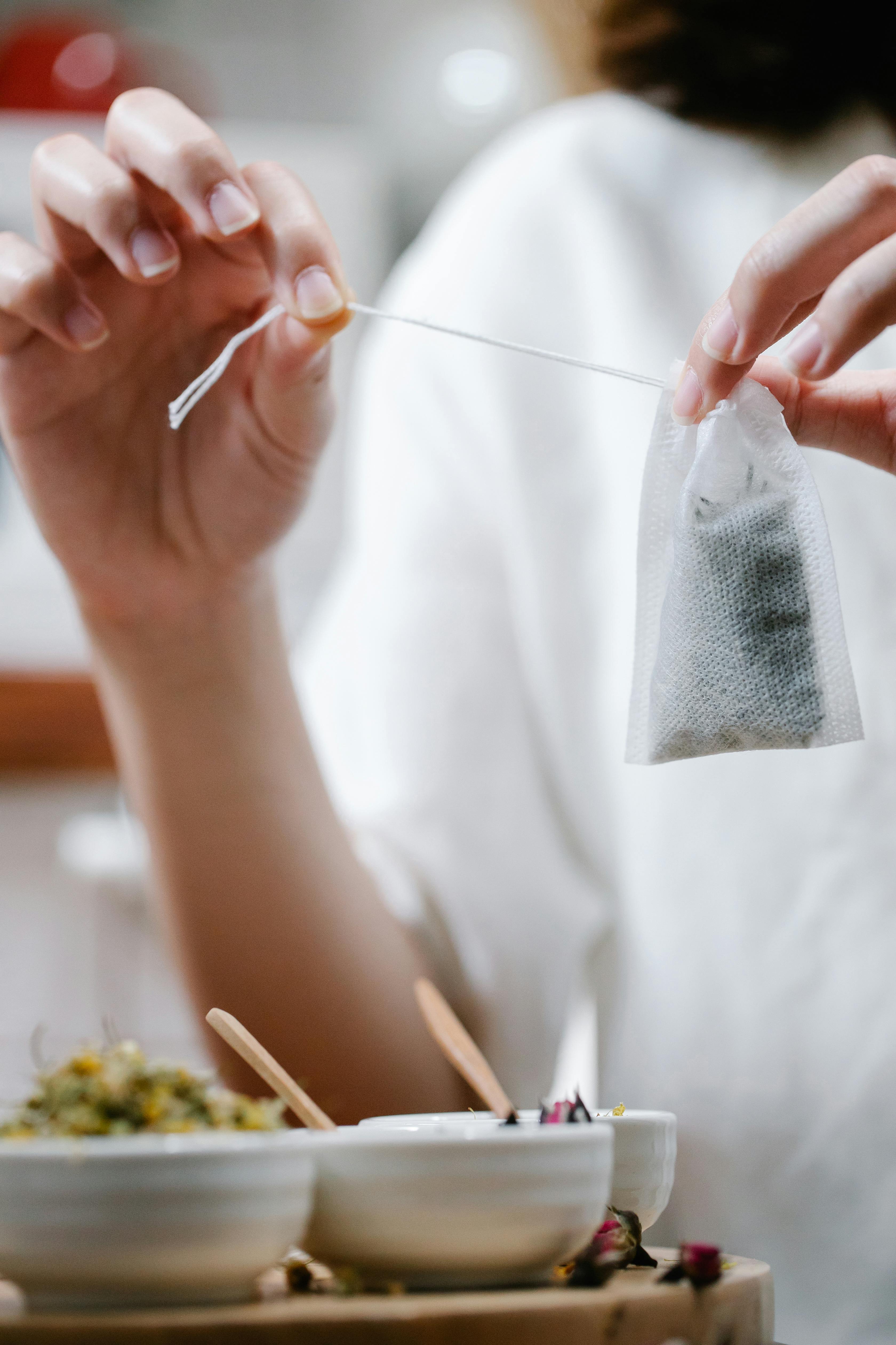 Close up of Female Hands Holding a Tea Bag and Herbs in Ceramic Bowls ...