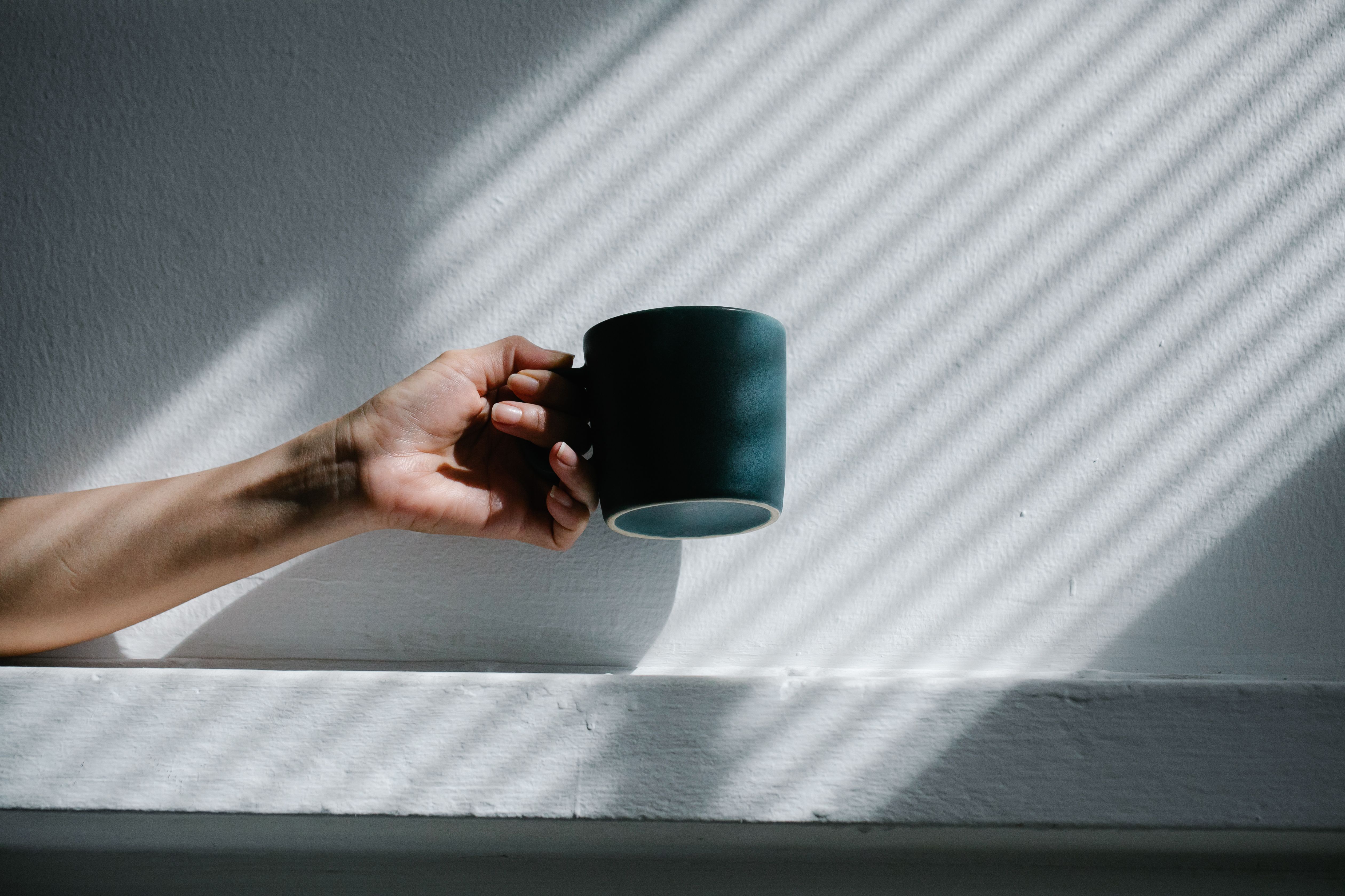 Hand Holding Mug Towards Sunlight · Free Stock Photo