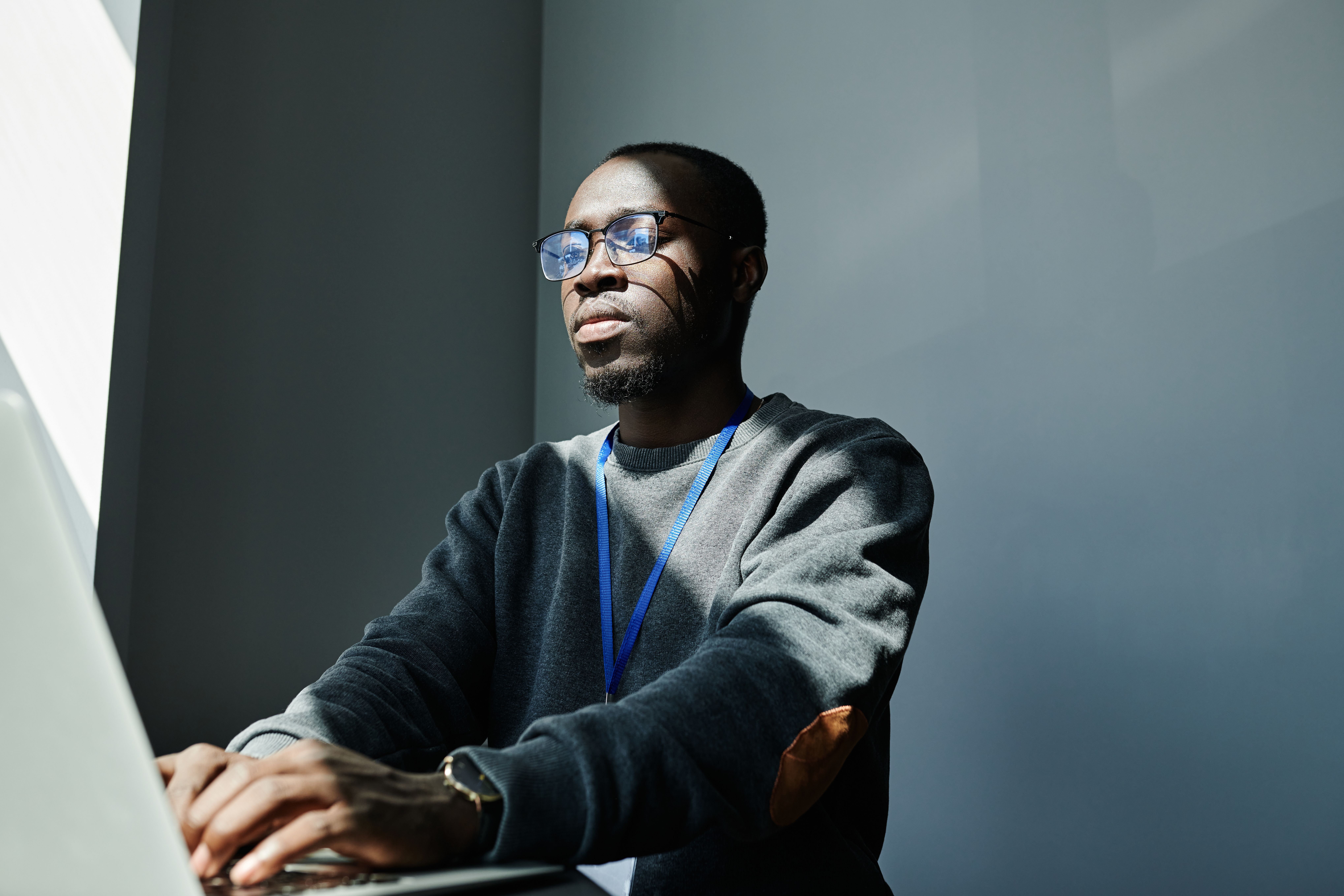 Man in Gray Sweater using a Laptop · Free Stock Photo