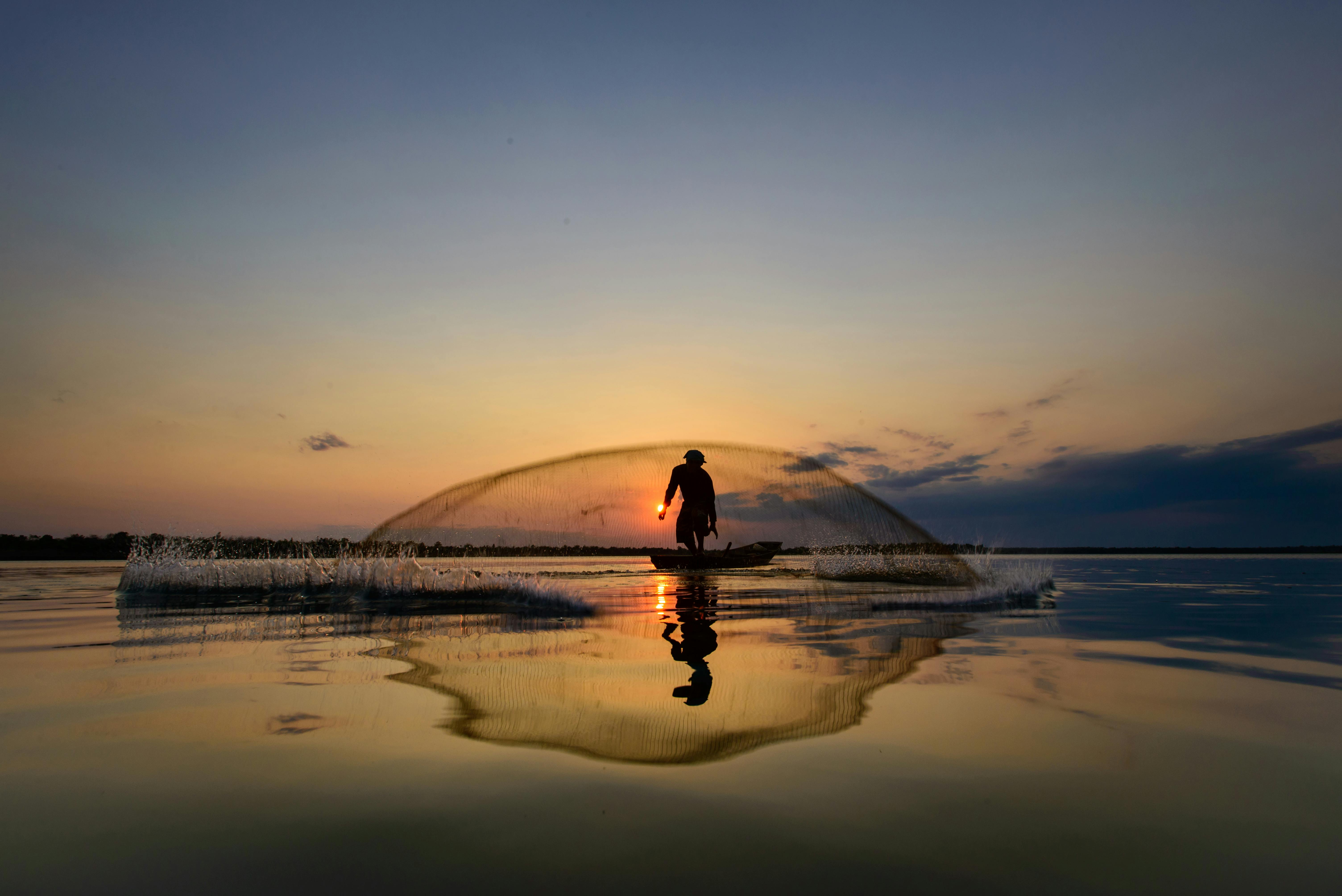 Fisherman Throwing a Net at Sunrise · Free Stock Photo