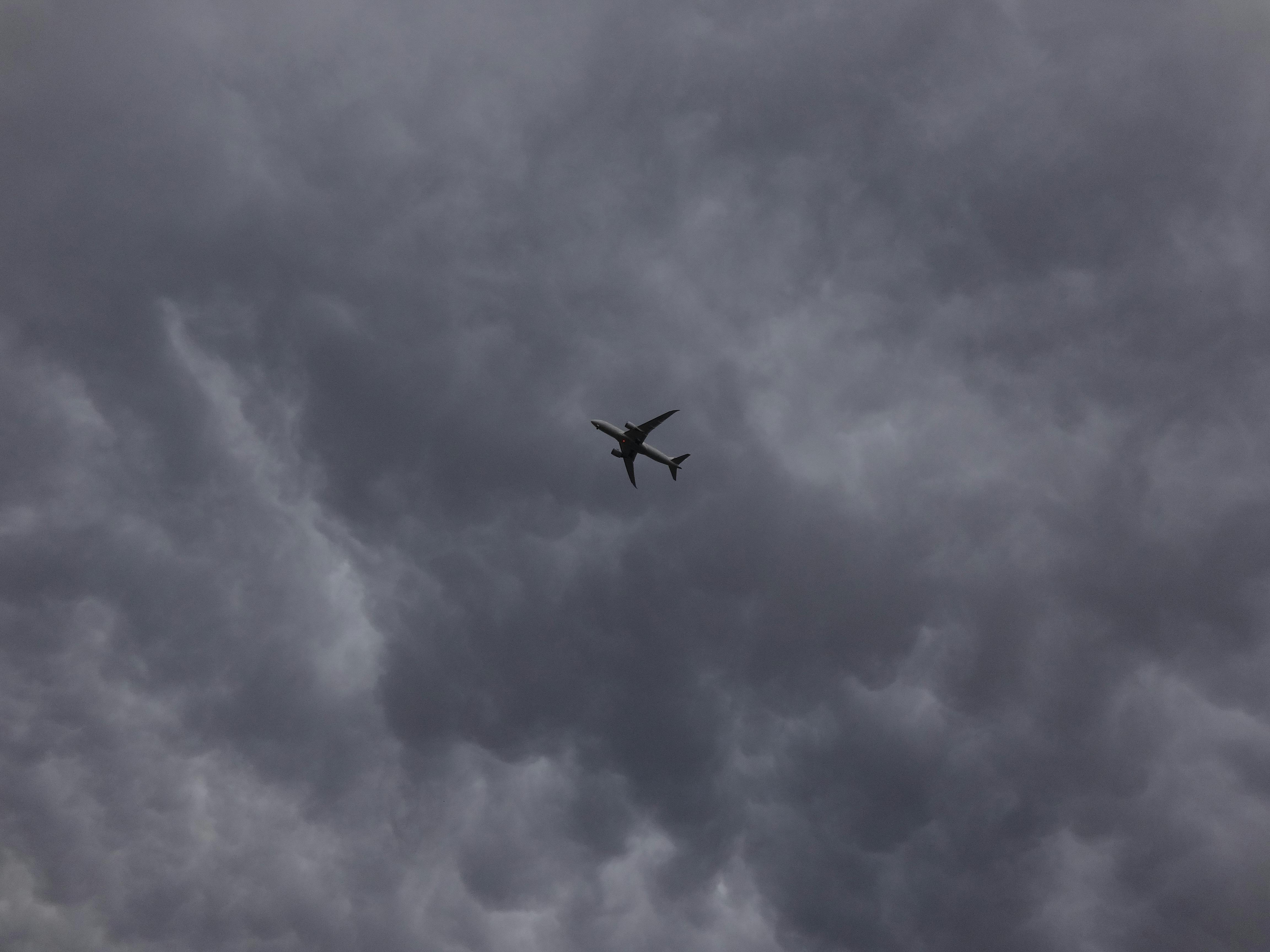 Airplane Flying Under the Dark Clouds · Free Stock Photo