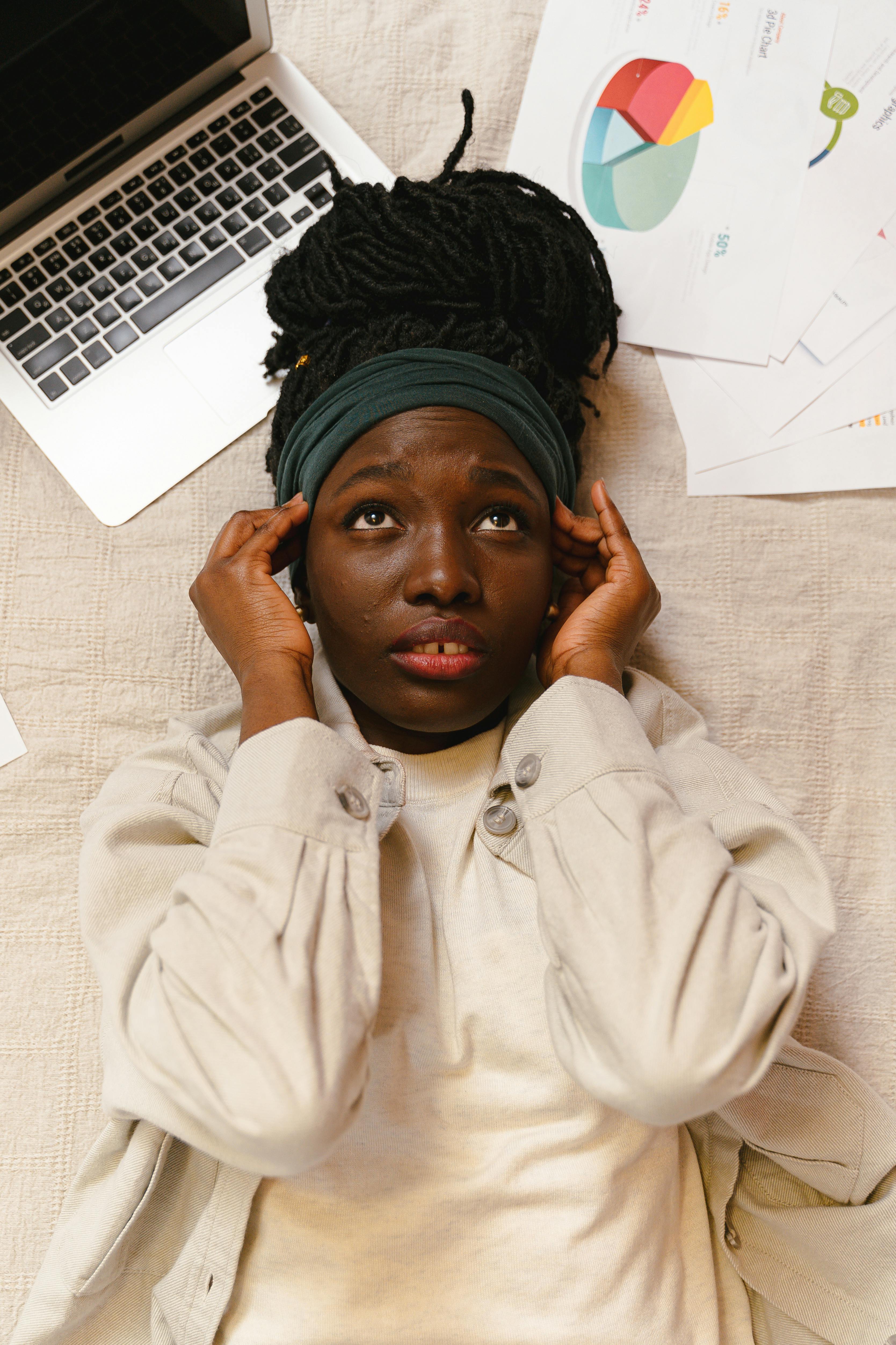 A Woman Thinking while Lying Down Near the Laptop · Free Stock Photo