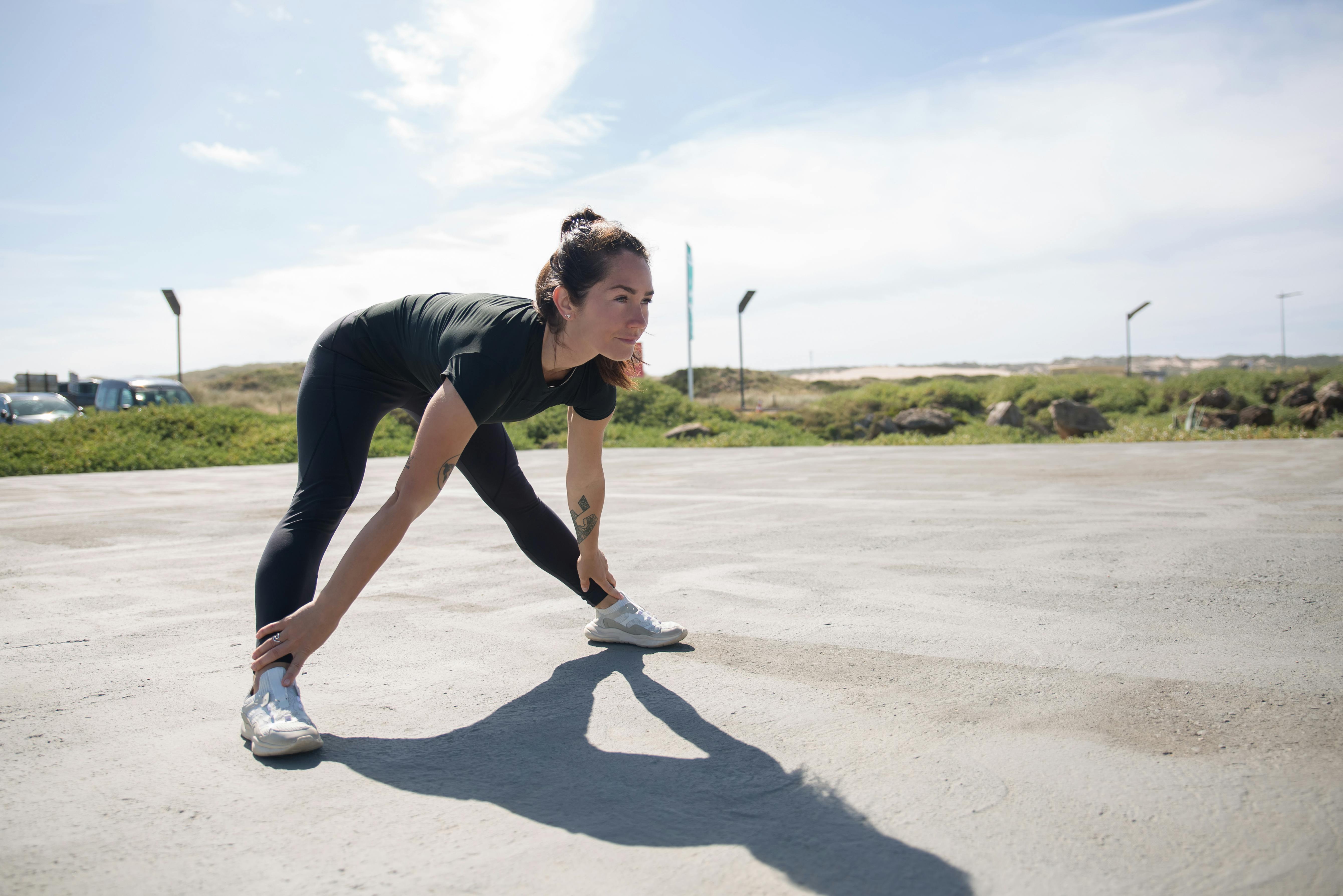 A Woman Bending Over While Standing on the Concrete Pavement · Free ...