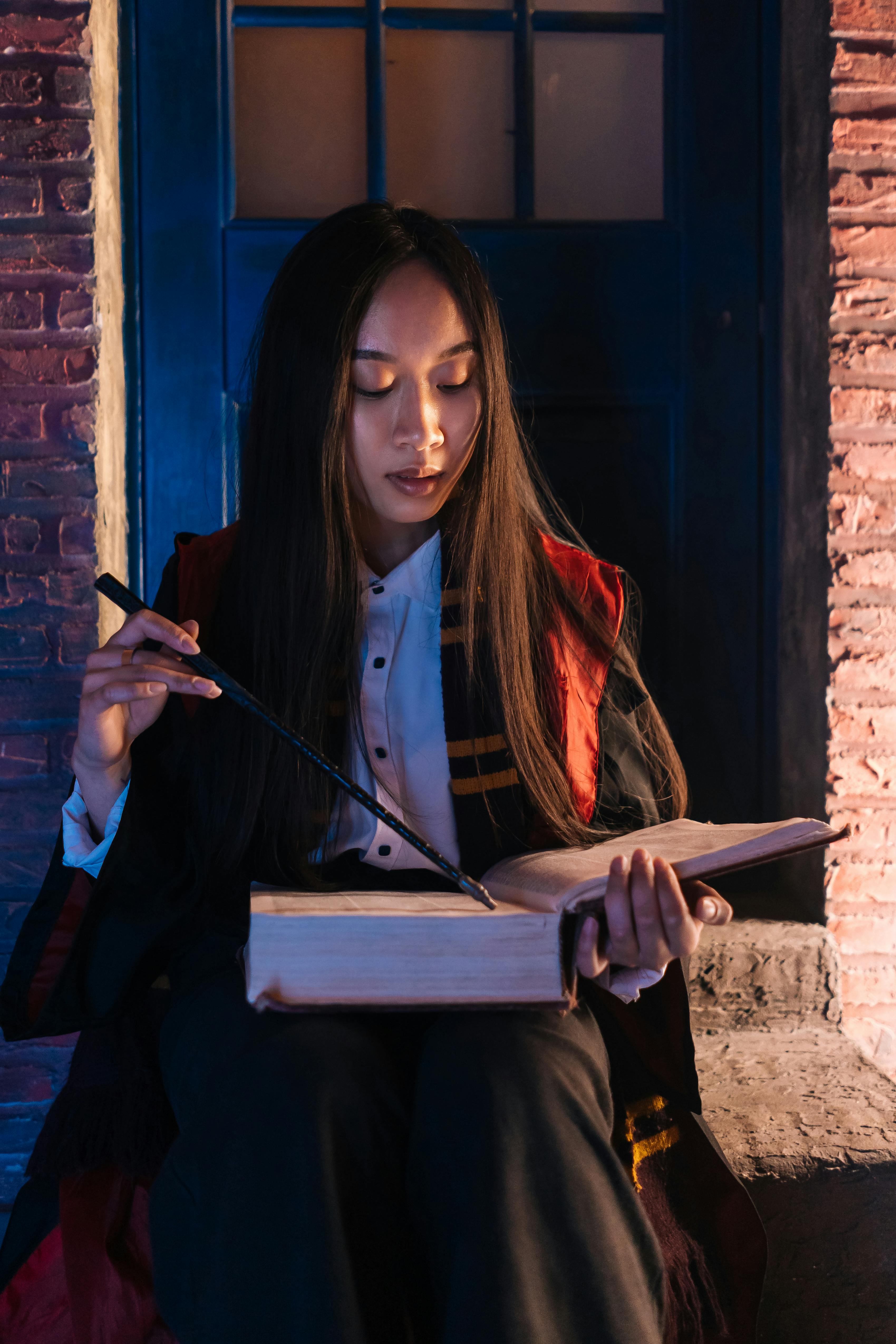 Woman Pointing Wand on Book Page · Free Stock Photo