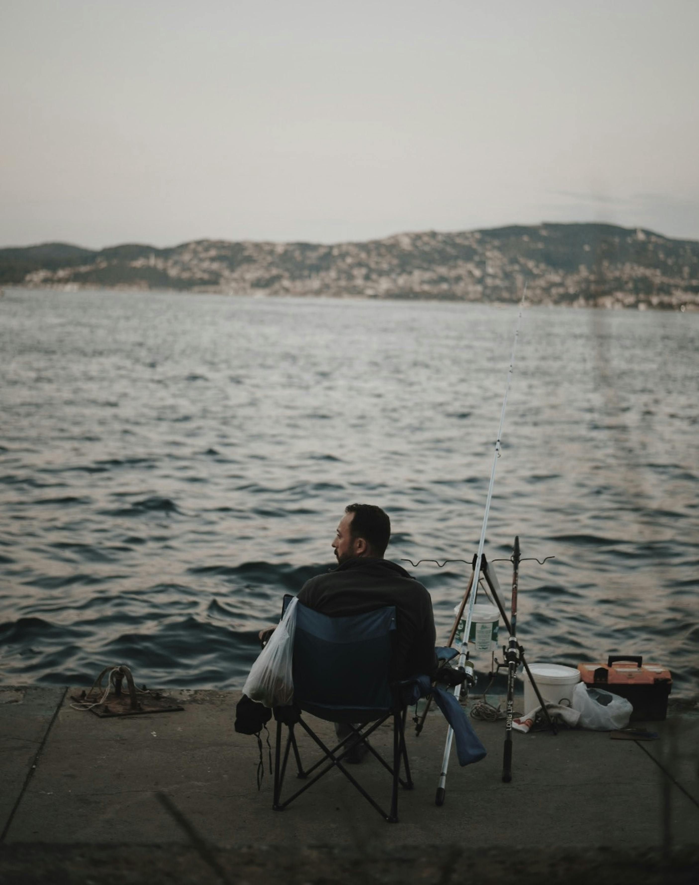 Angler Sitting in Chair by Sea · Free Stock Photo
