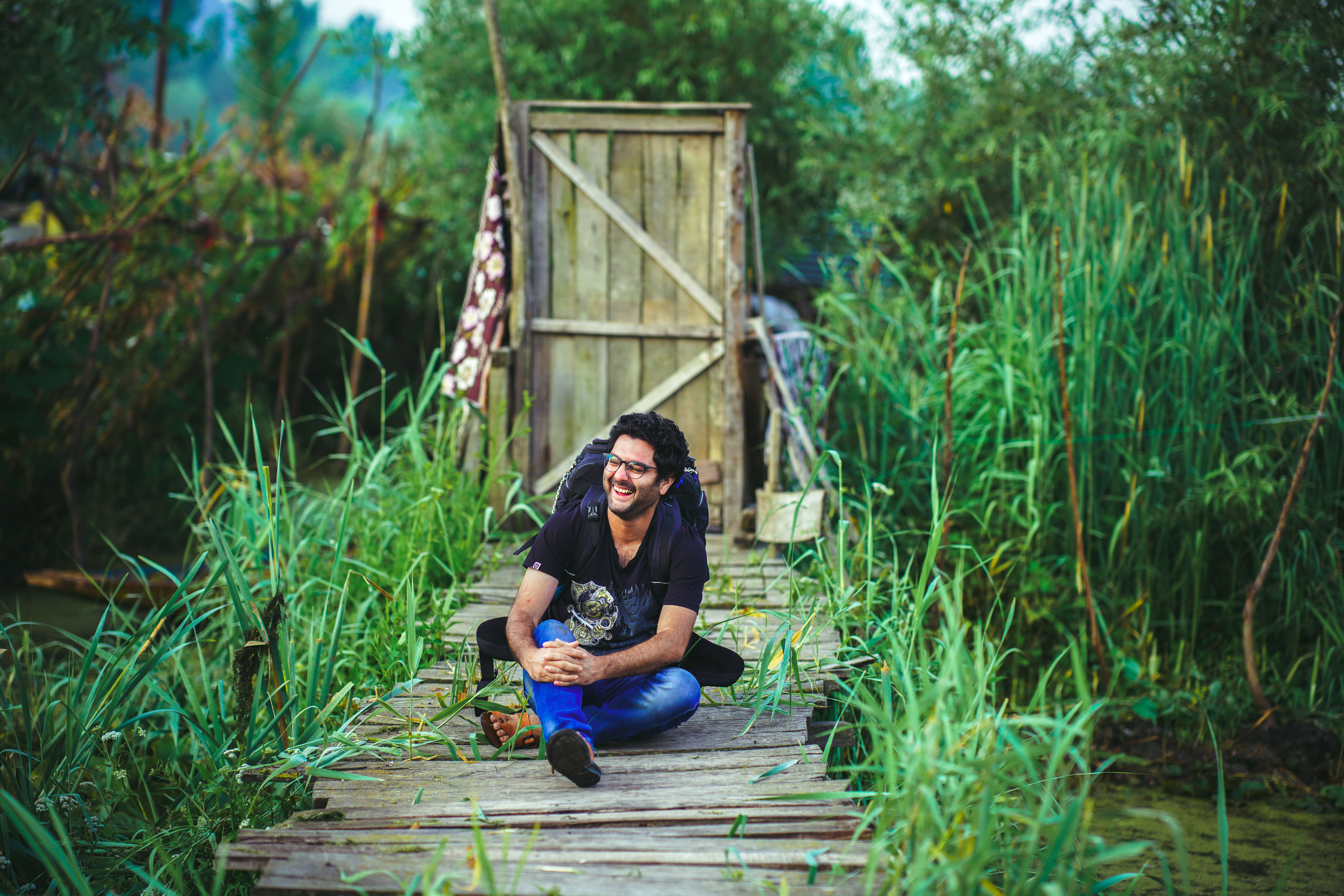 Man Sitting on the Boardwalk Laughing · Free Stock Photo