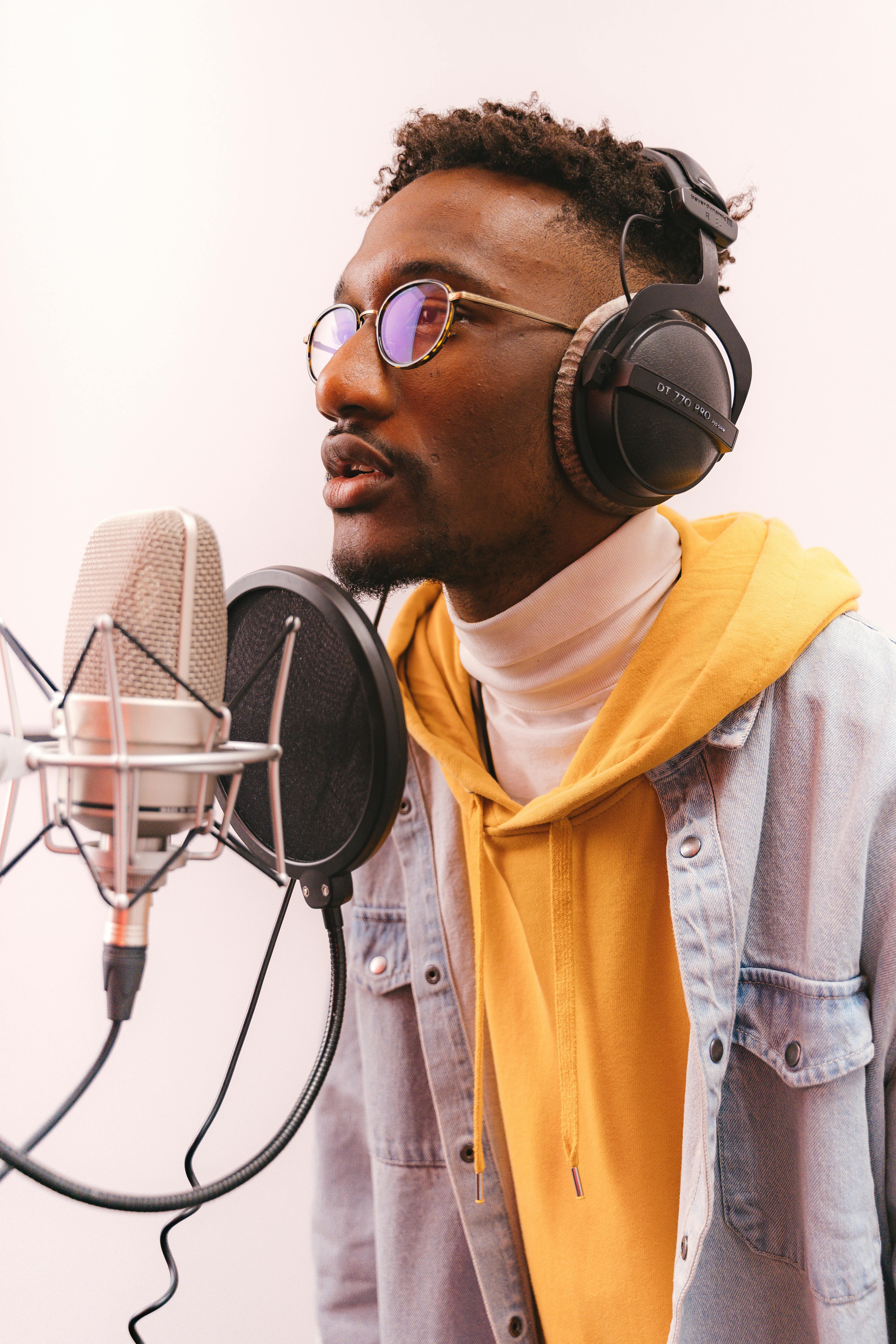 Man in Hoodie and Denim Jacket standing in front of a Mic Condenser ...