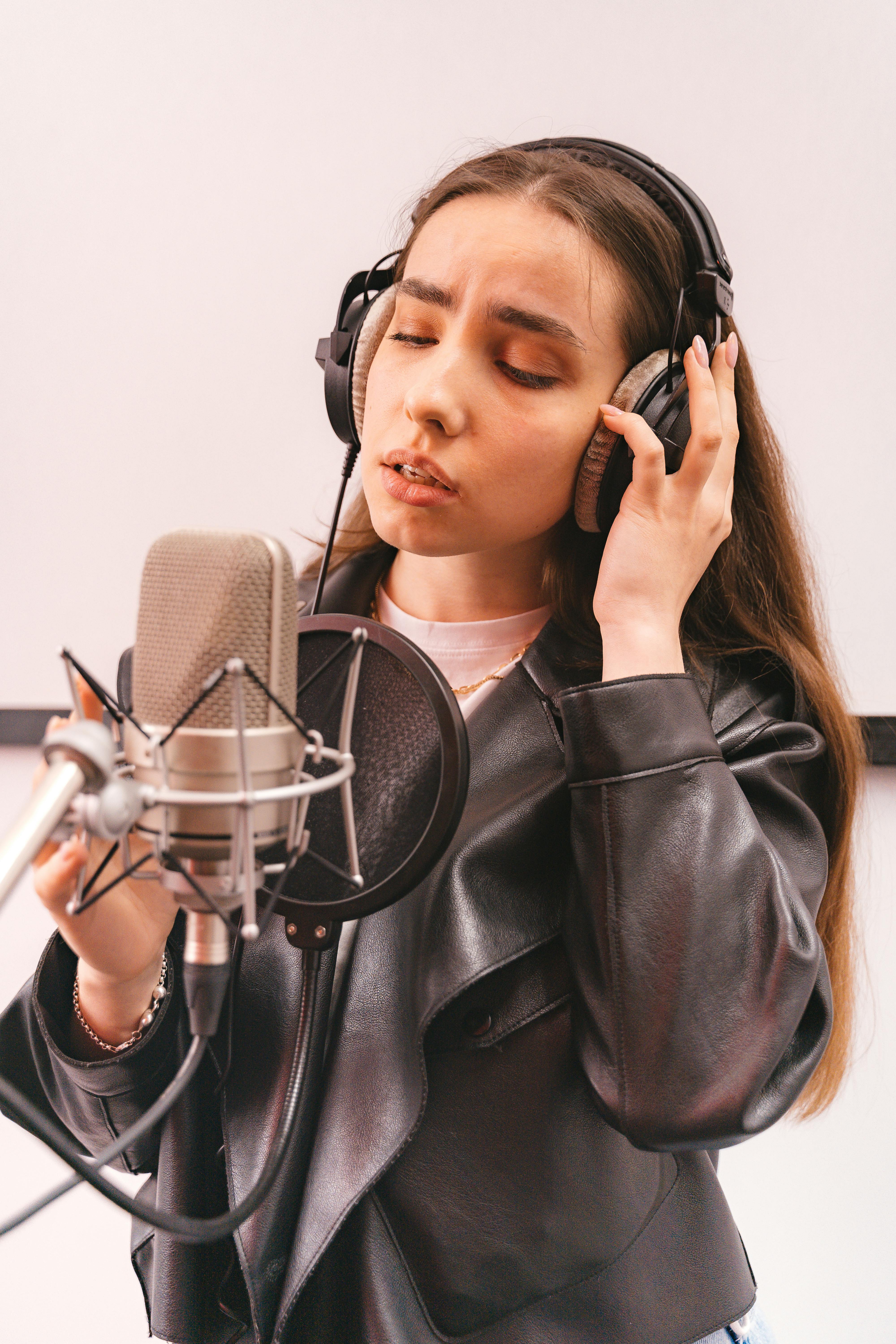 A Woman Wearing a Leather Jacket and Headphones Singing · Free Stock Photo