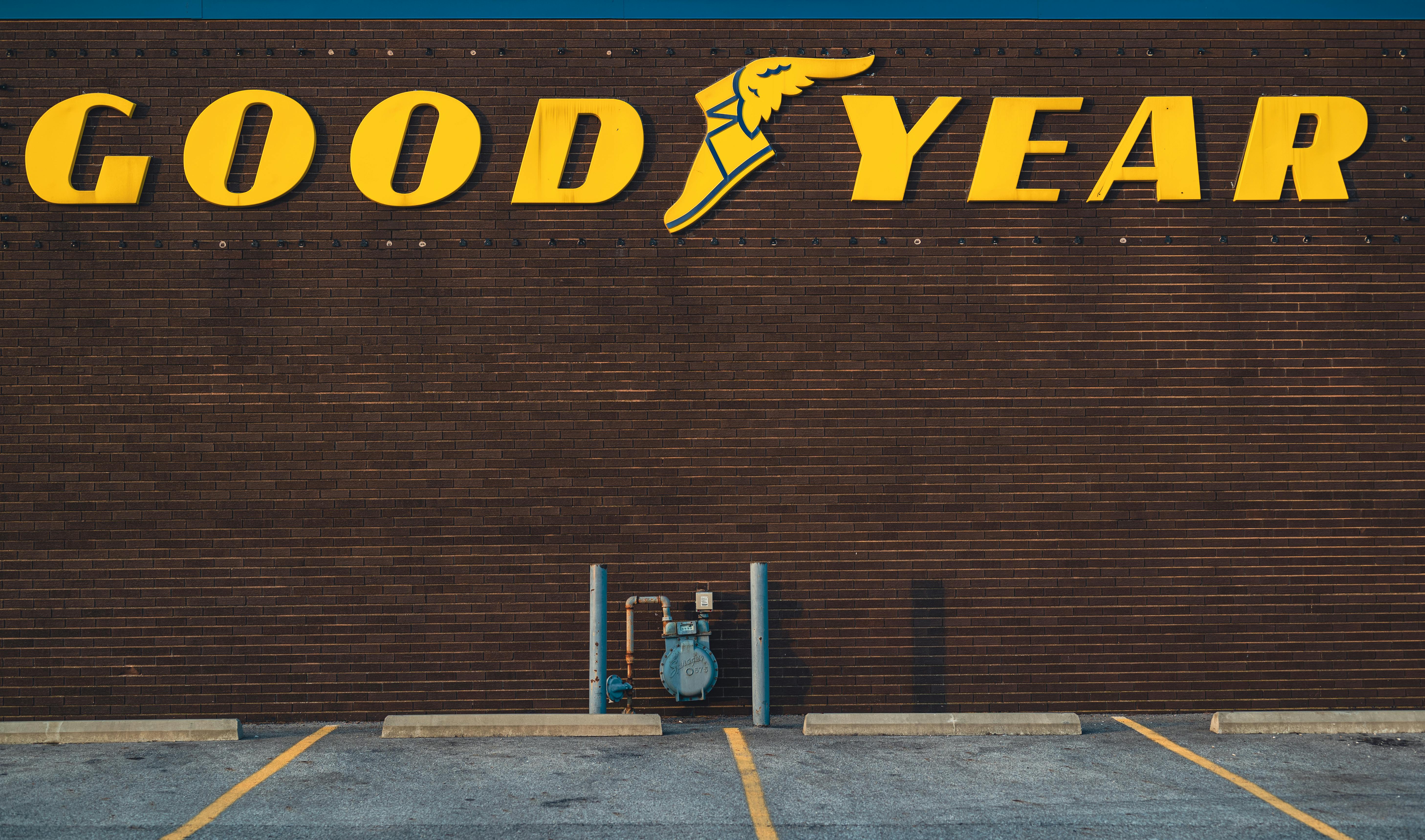 Yellow Good Year Signage on Brown Brick Wall · Free Stock Photo