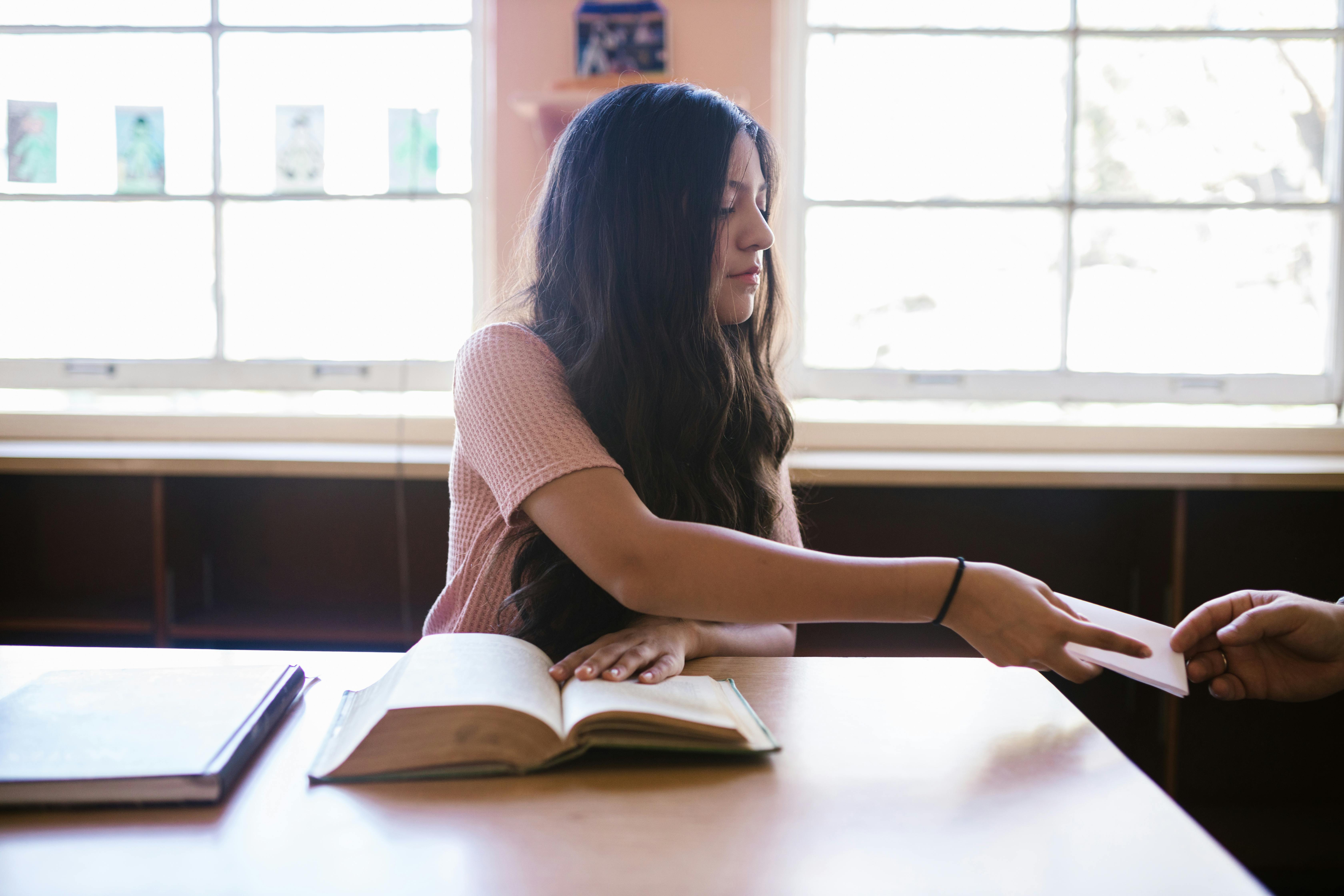 A Student Passing a Piece of Paper to another Person · Free Stock Photo