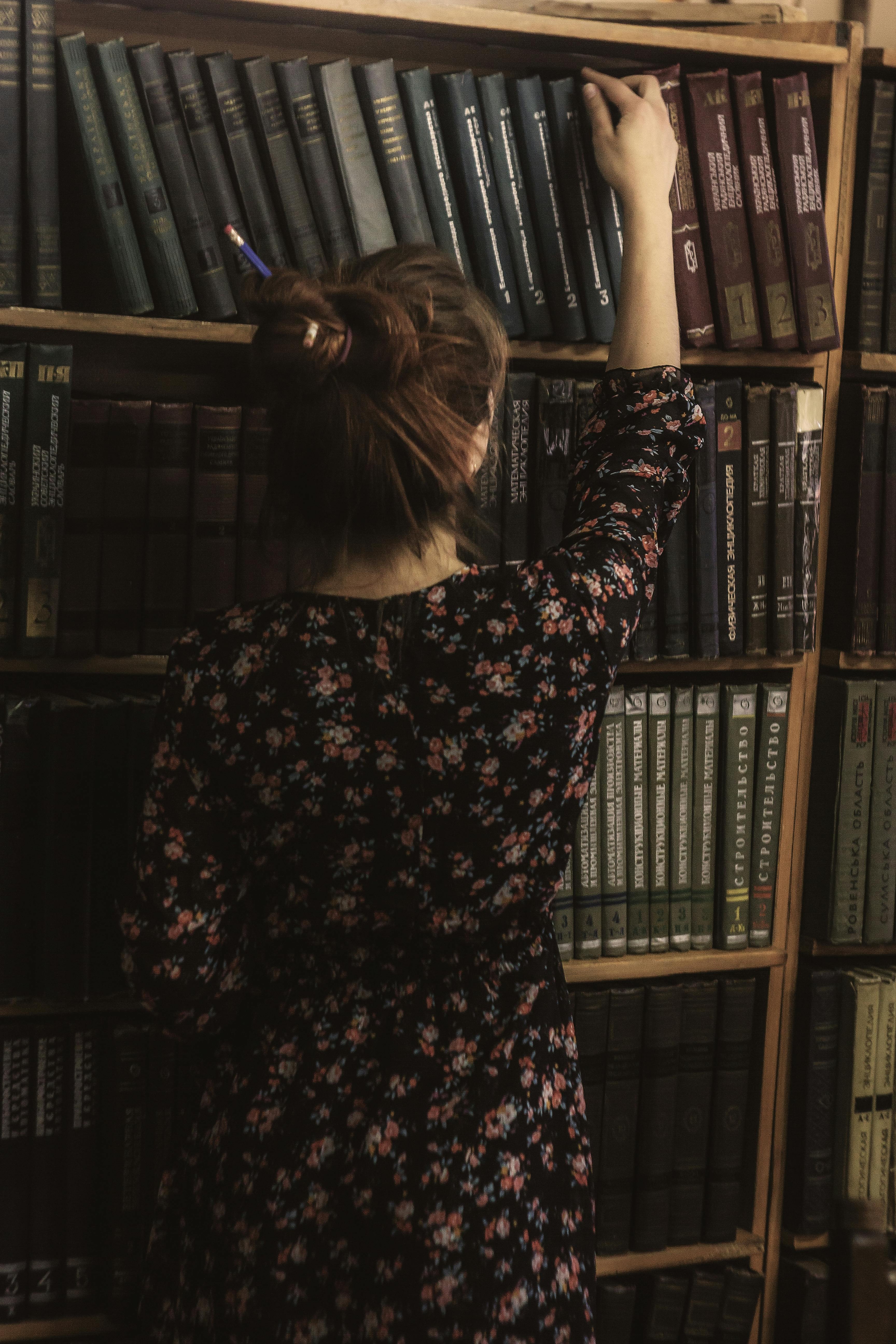 Back View of a Woman near a Bookshelf · Free Stock Photo
