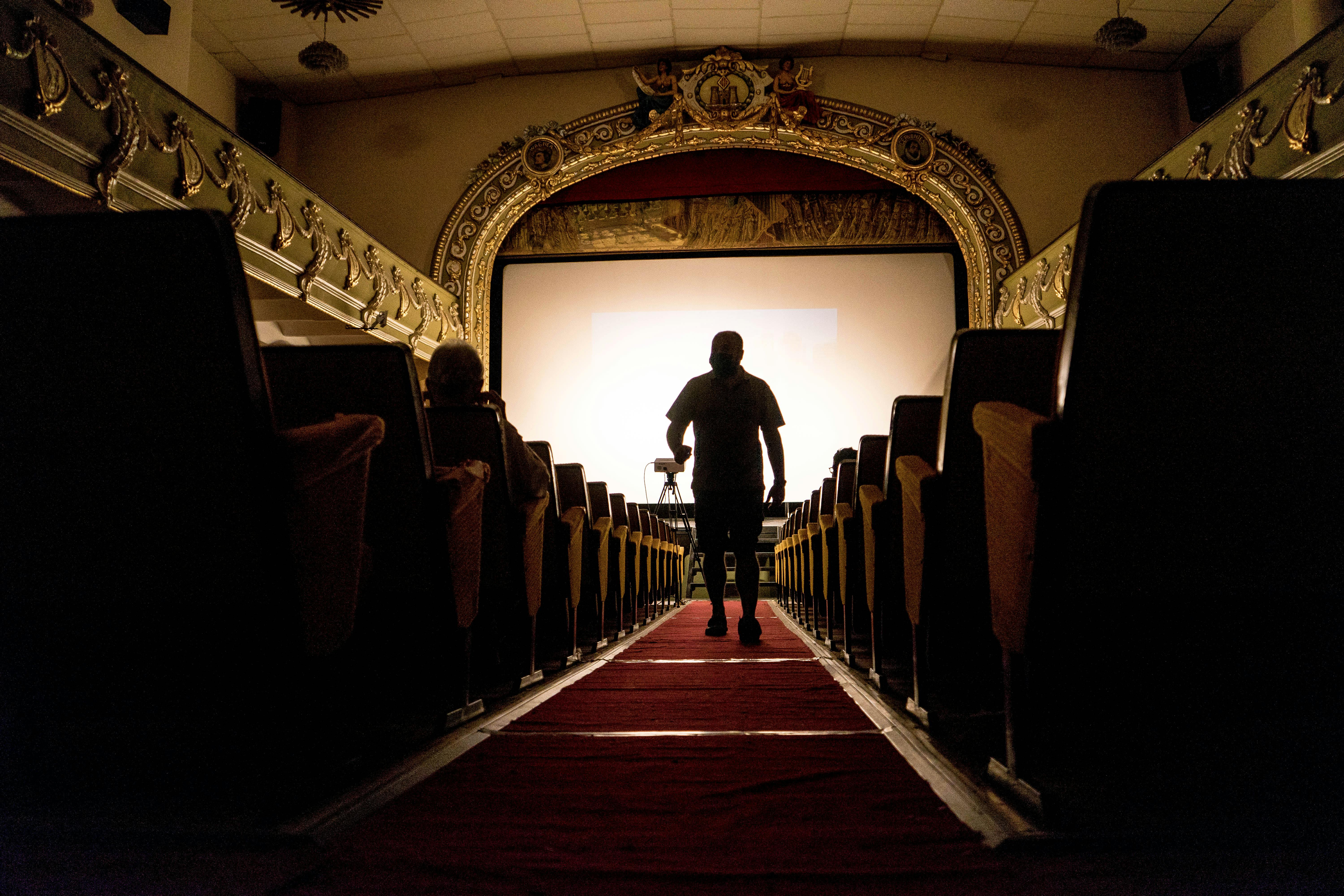 Person Walking on Red Carpet Aisle Inside Movie Theatre · Free Stock Photo