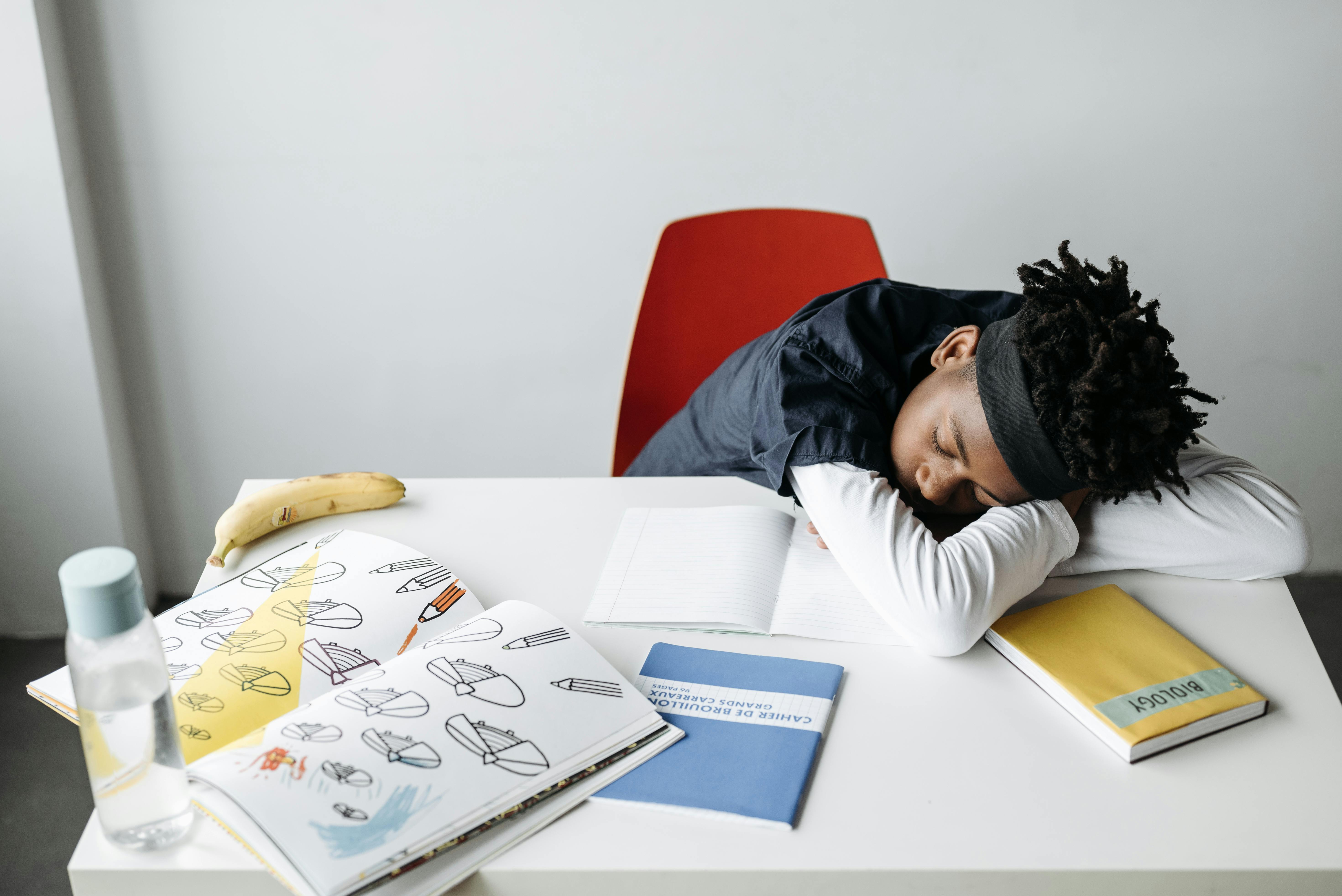 A Kid Sleeping on White Desk with Textbooks · Free Stock Photo