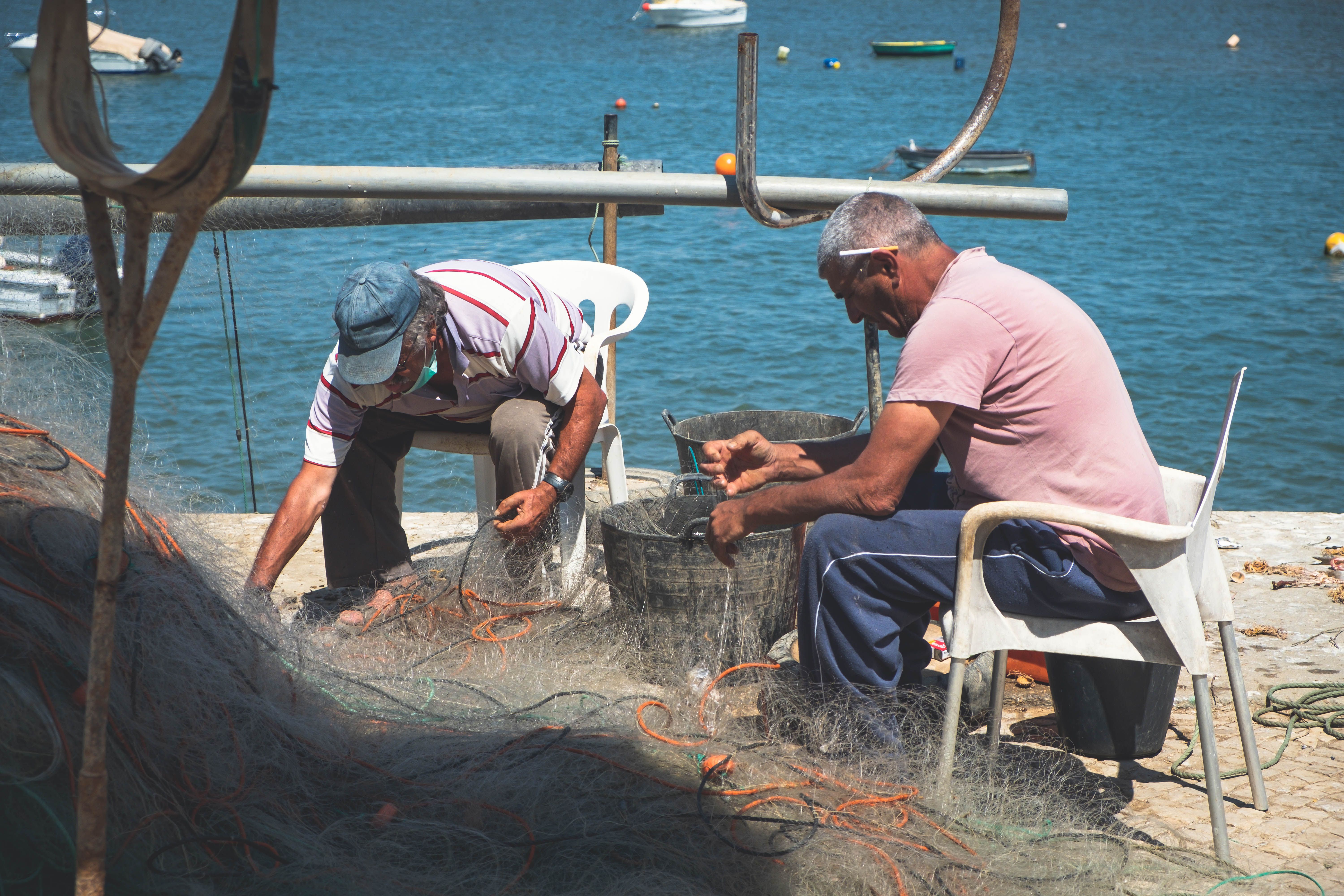 Fishermen Sitting and Working on Shore · Free Stock Photo