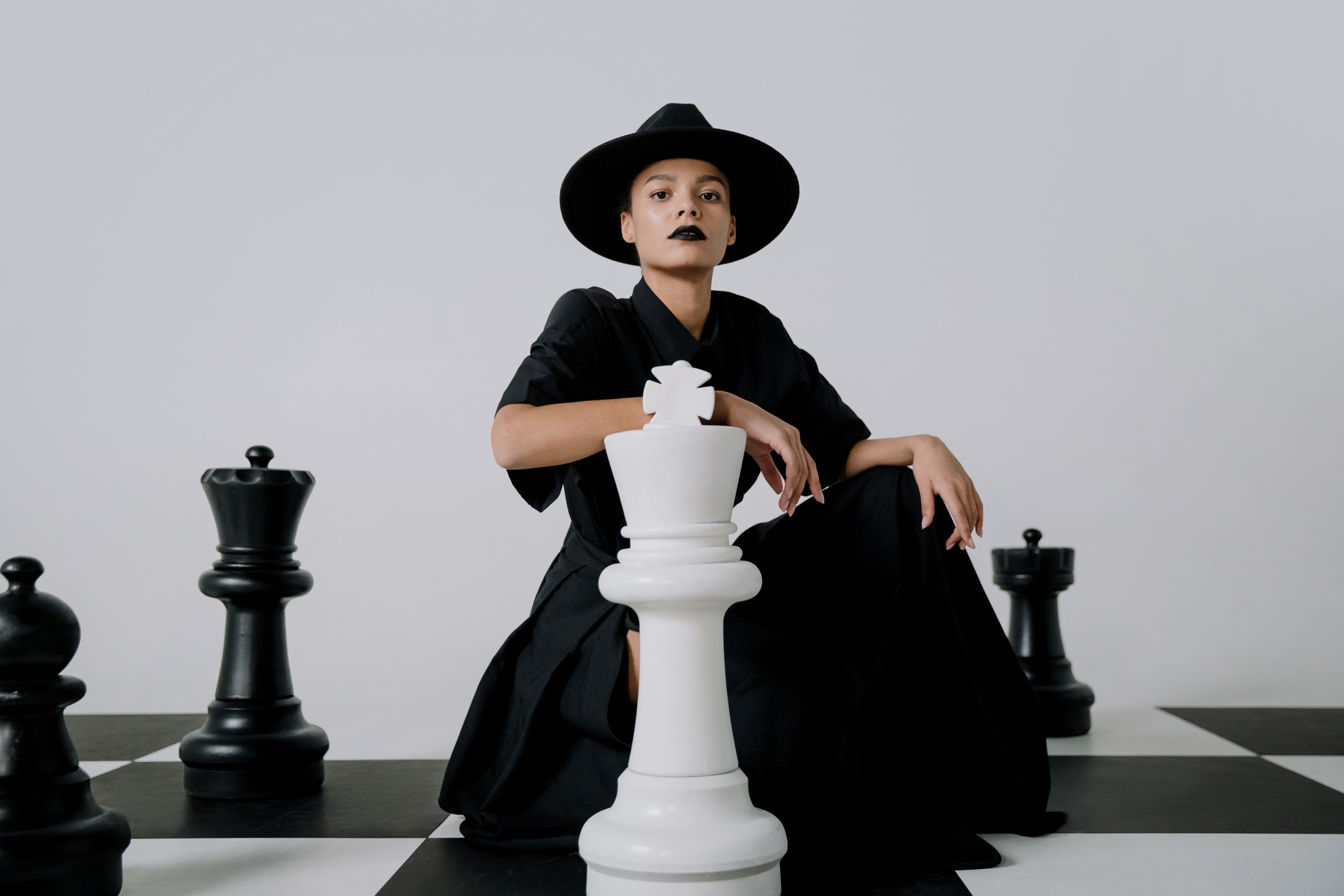 A Person in a Black Top and Black Hat Holding a Chess Piece · Free ...
