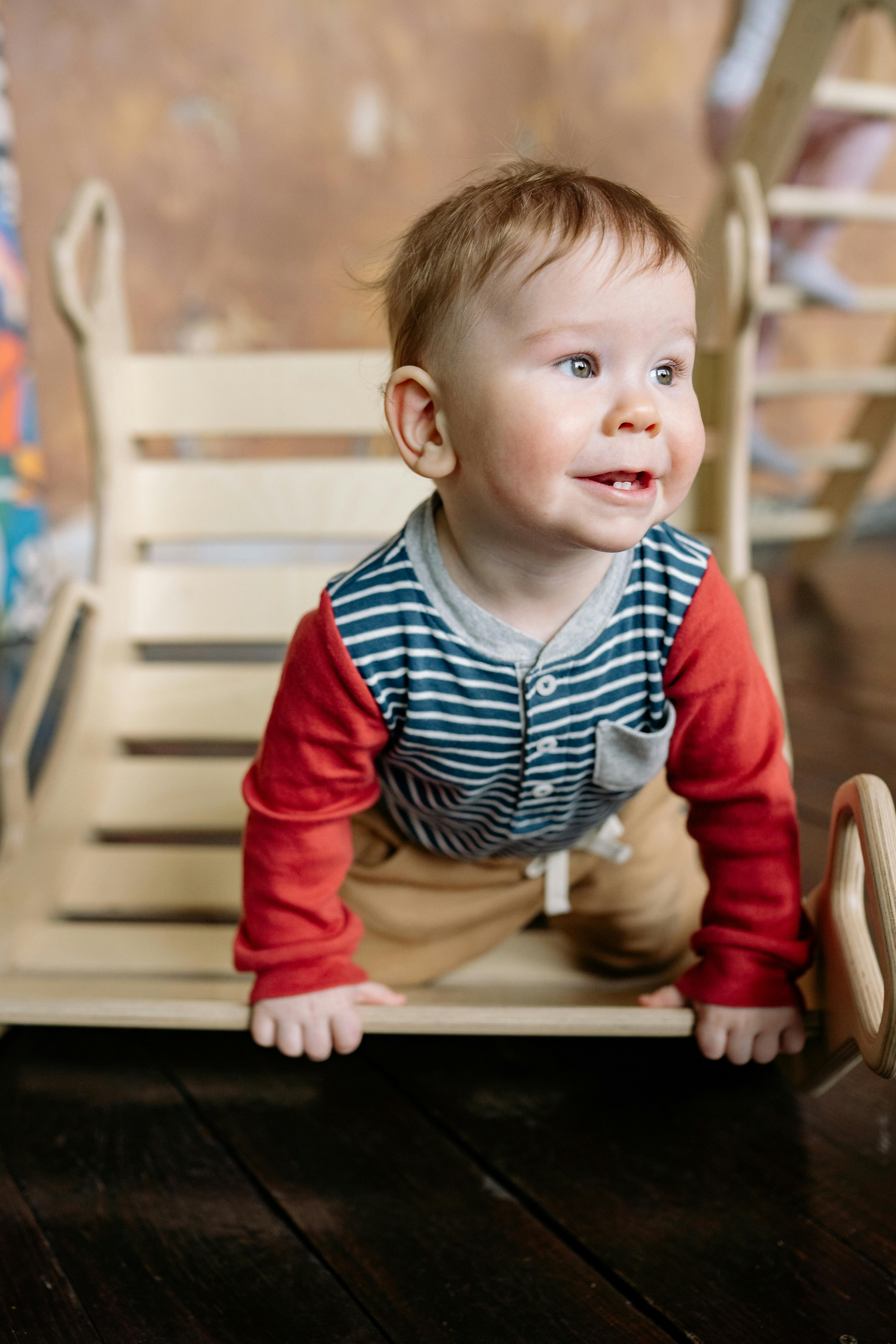 A Baby Boy Kneeling on a Wooden Chair · Free Stock Photo