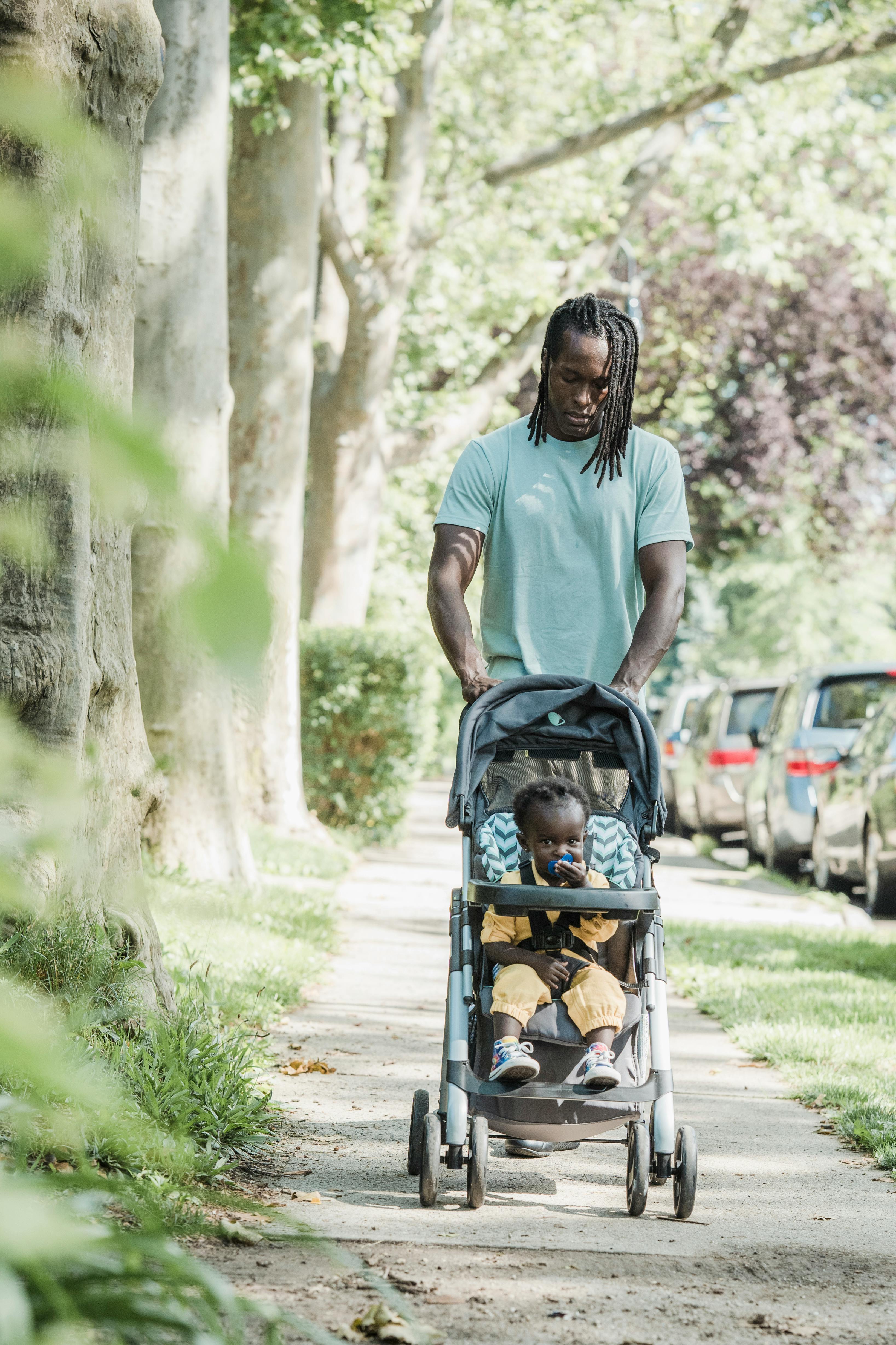 Father Pushing a Baby Stroller · Free Stock Photo