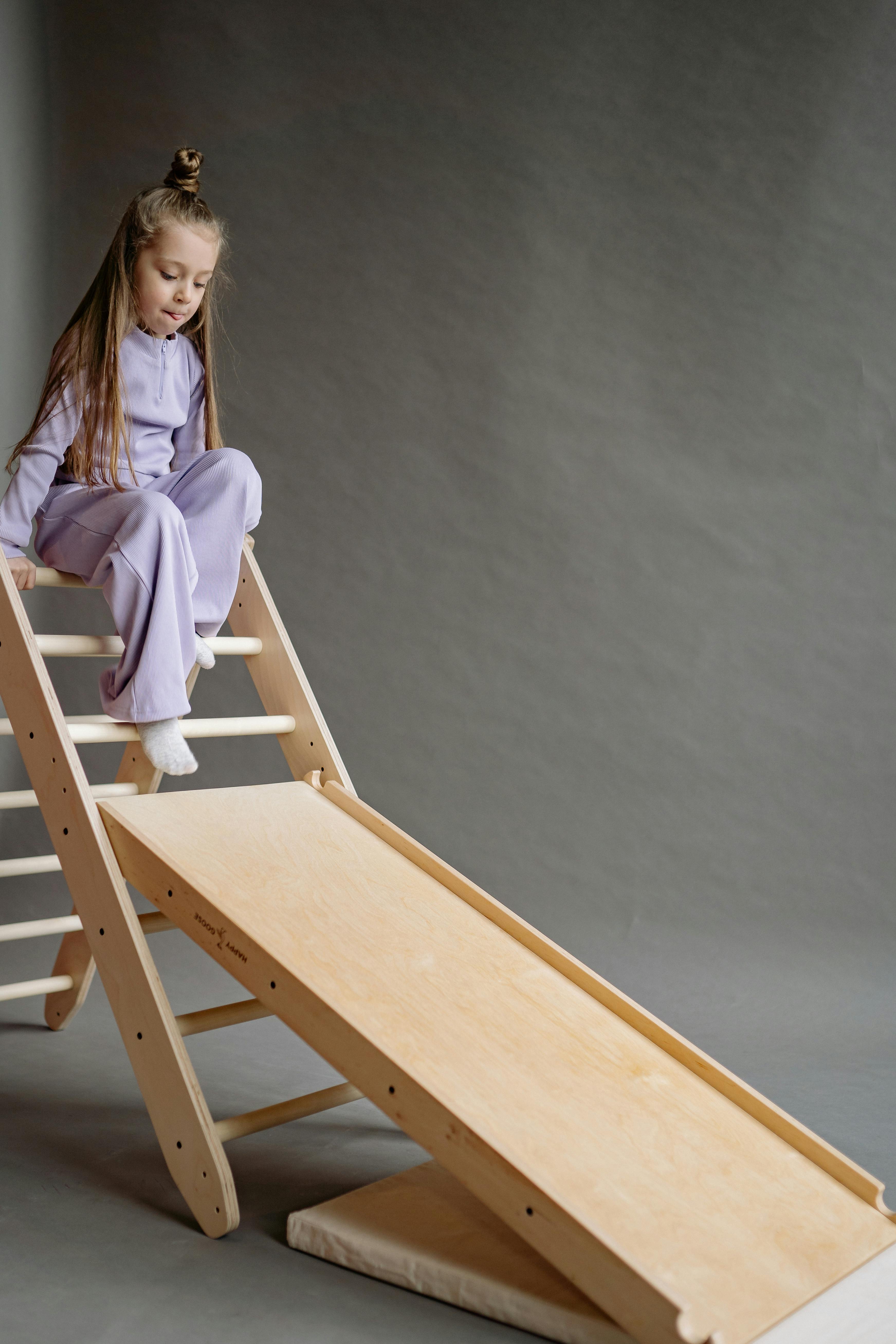 Girl Sitting on Wooden Reversible Rockwall/Slide Ramp · Free Stock Photo