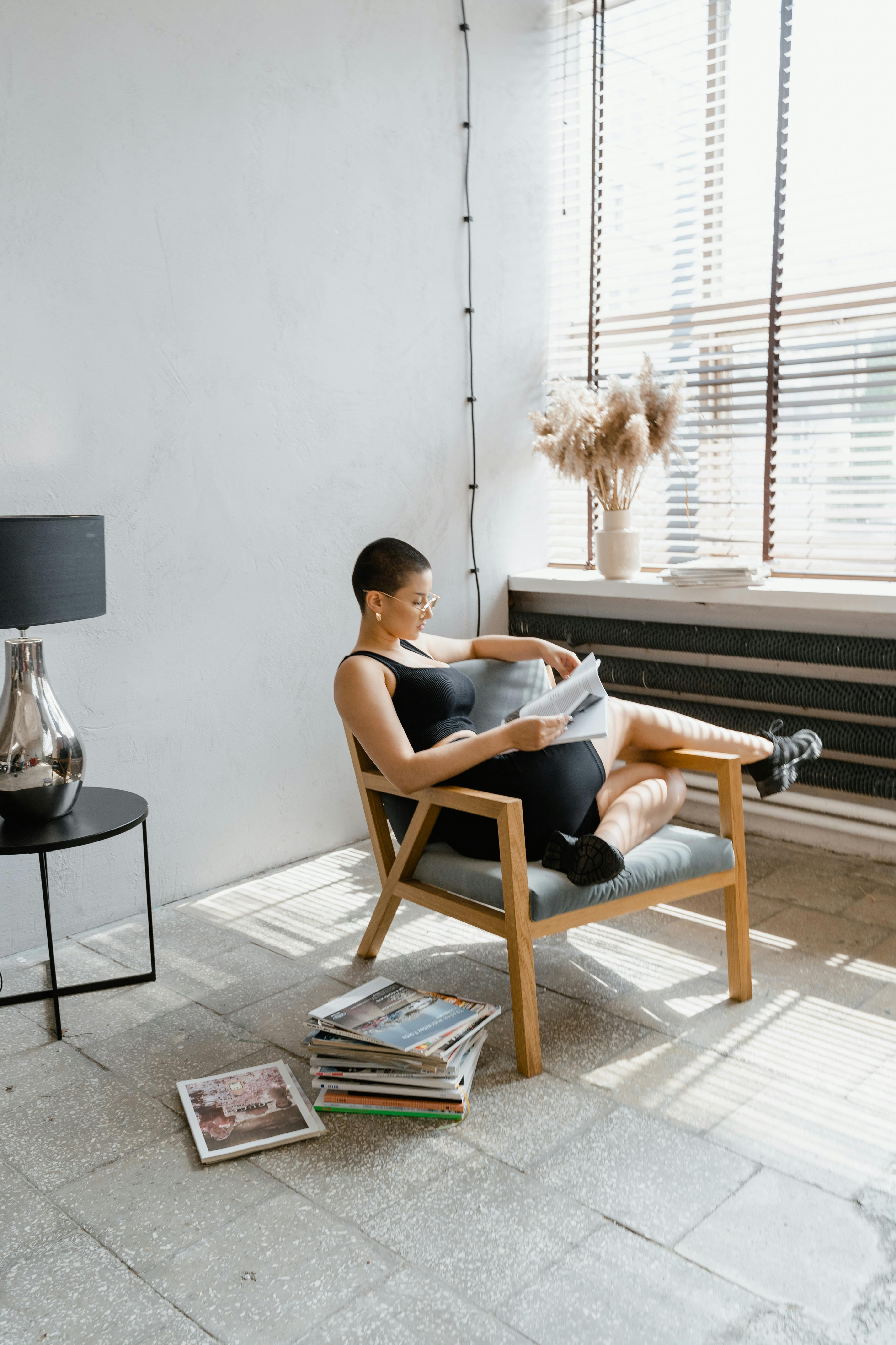A Woman Reading a Book while Sitting on a Chair · Free Stock Photo