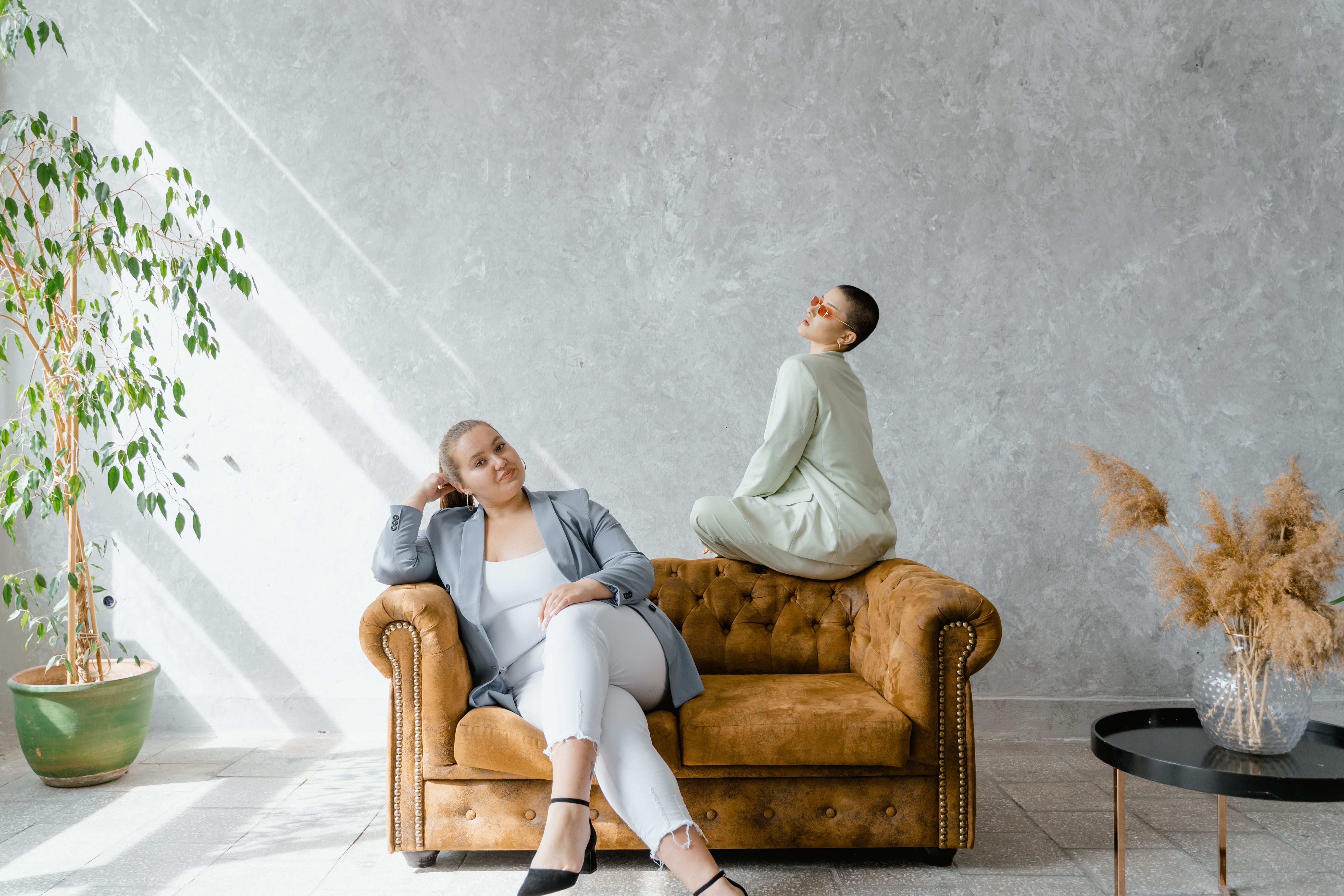Two Women Sitting on Brown Couch · Free Stock Photo
