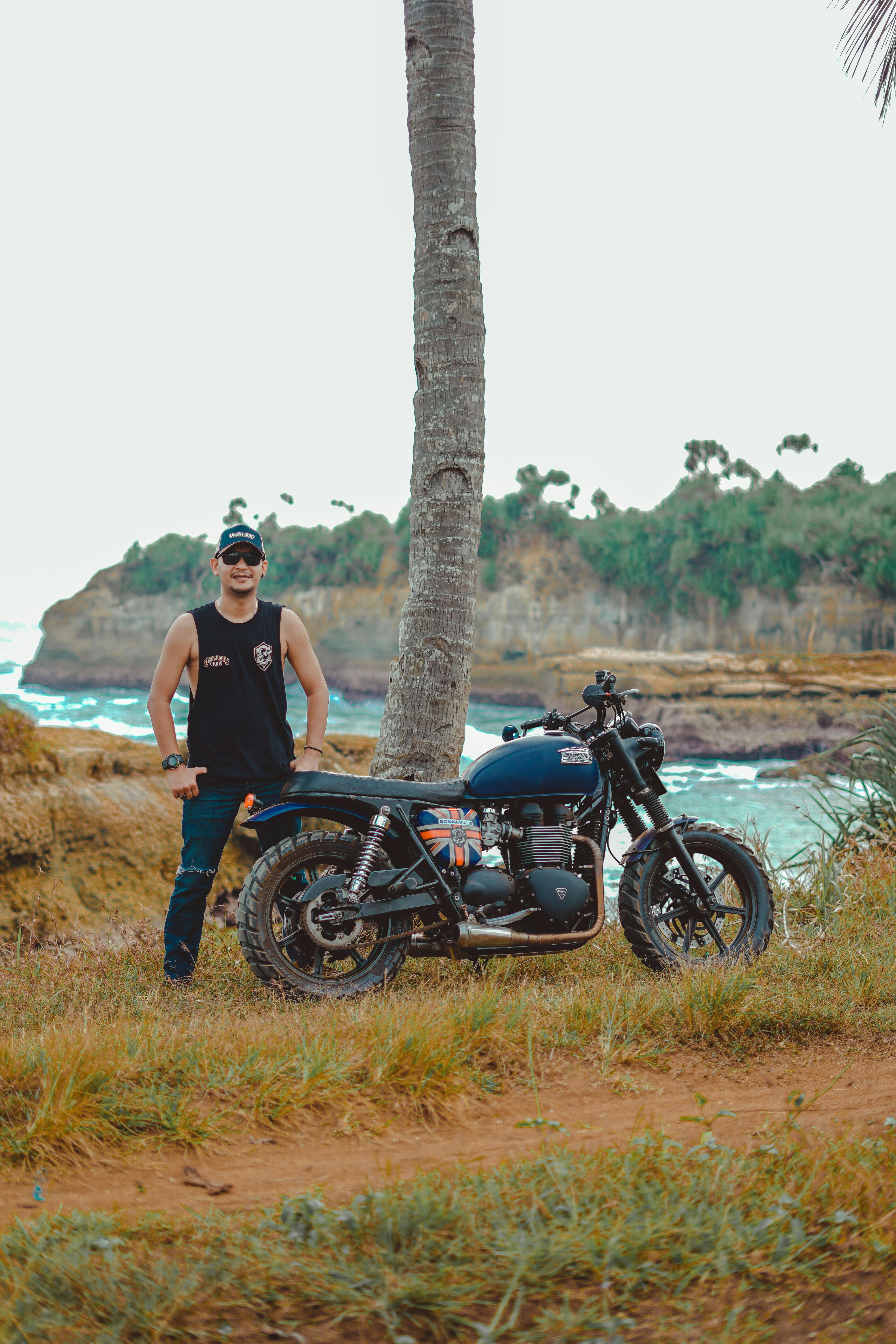 Man Standing Beside Motorcycle Near Tree · Free Stock Photo