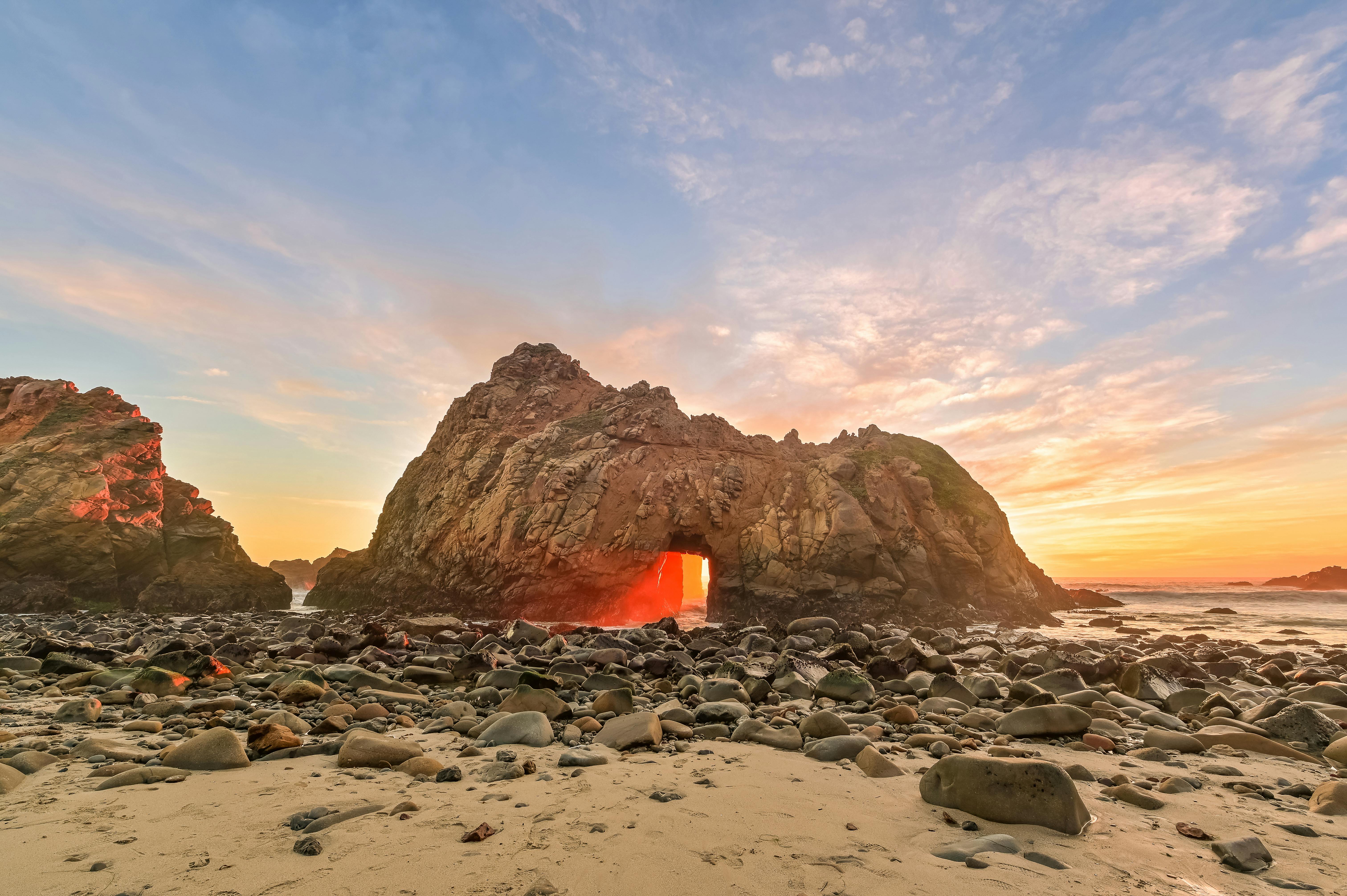 Sunlight Coming Through a Rocky Arch in a Beach · Free Stock Photo