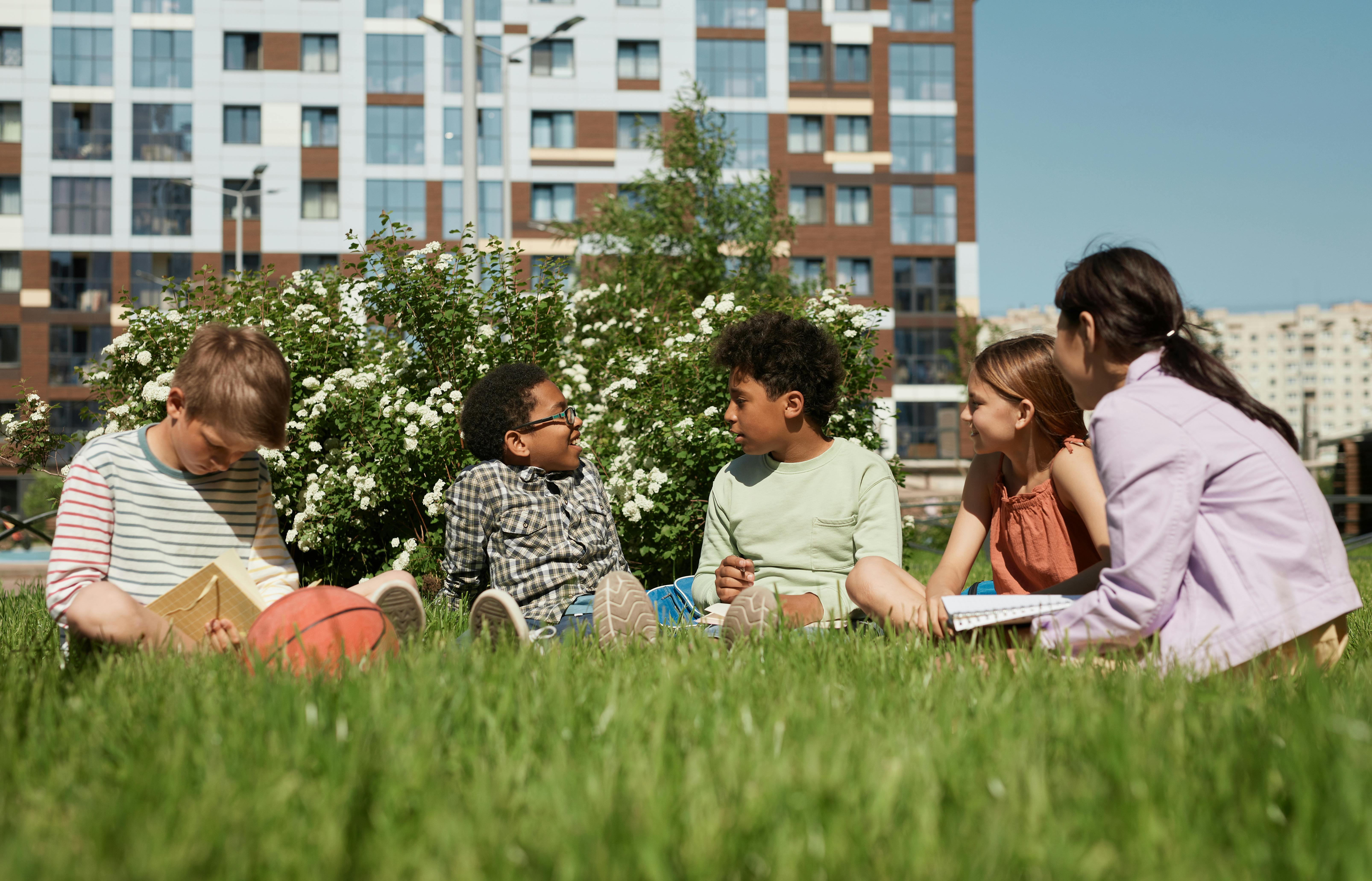 Group of Kids Sitting on the Grass with a Basketball Ball and Notebooks ...