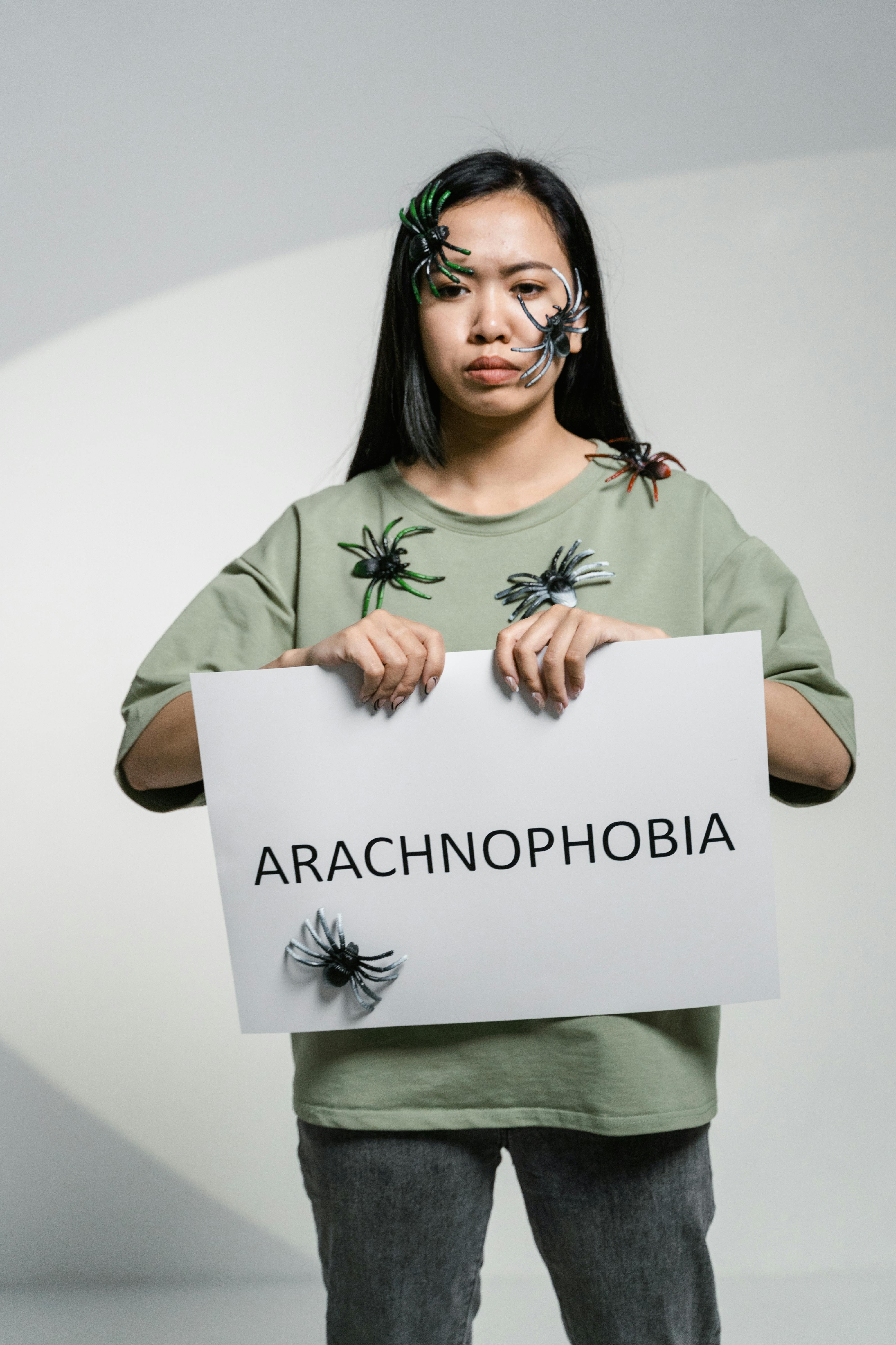 A Fearful Woman Holding a Sign of Arachnophobia · Free Stock Photo