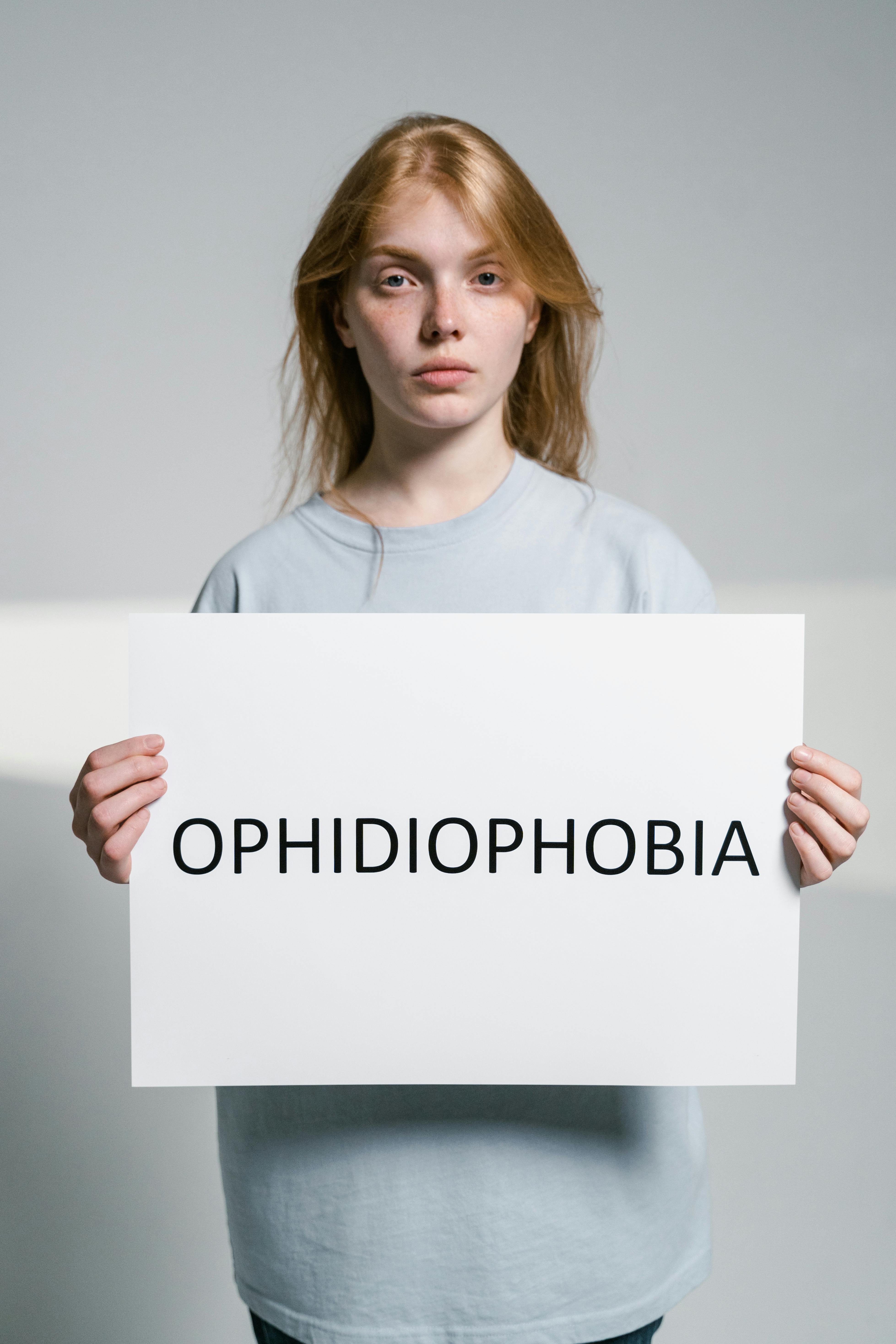 A Woman Holding a Sign of Ophidiophobia · Free Stock Photo