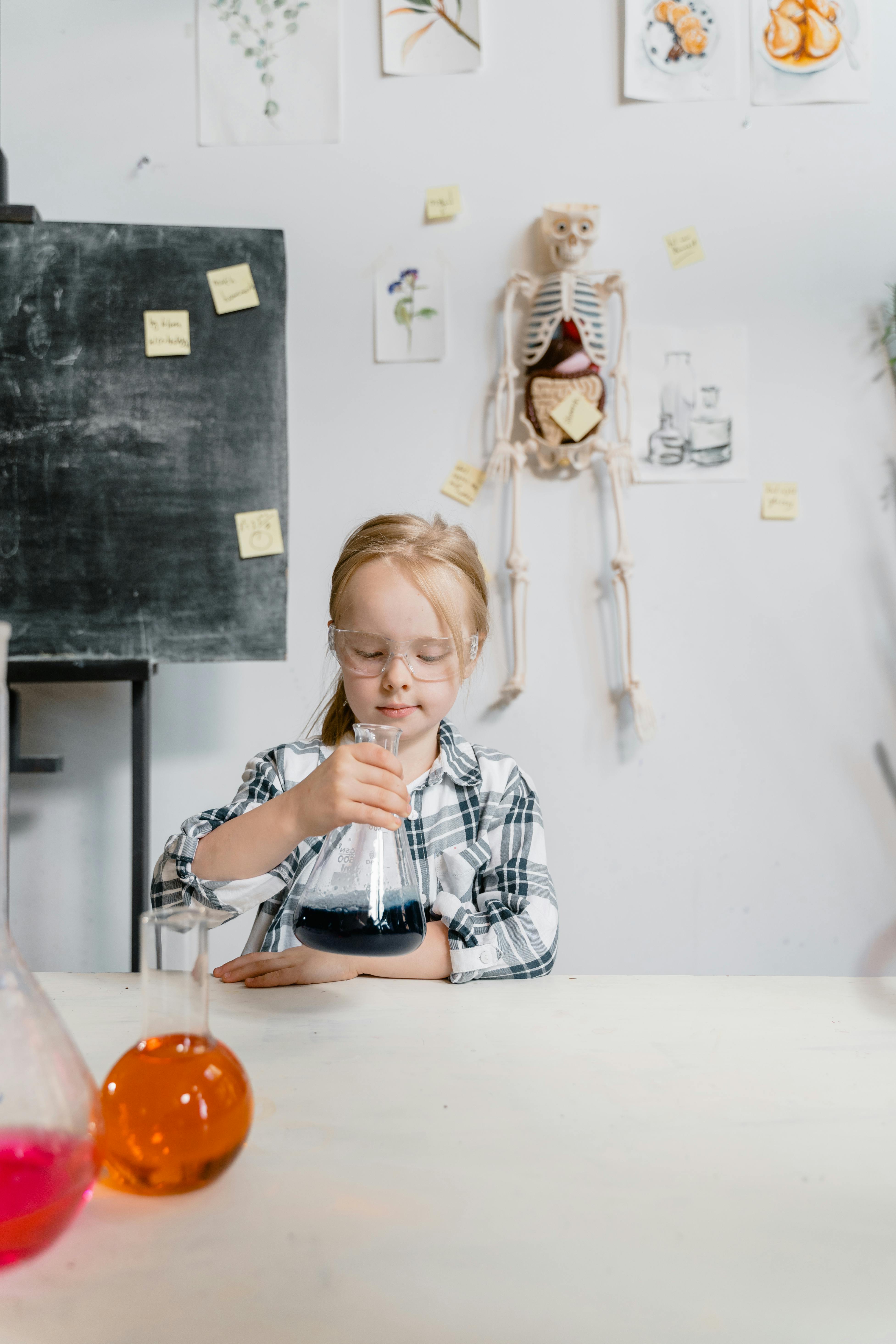 A Kid Wearing Safety Glasses while Looking at the Flask he is Holding ...