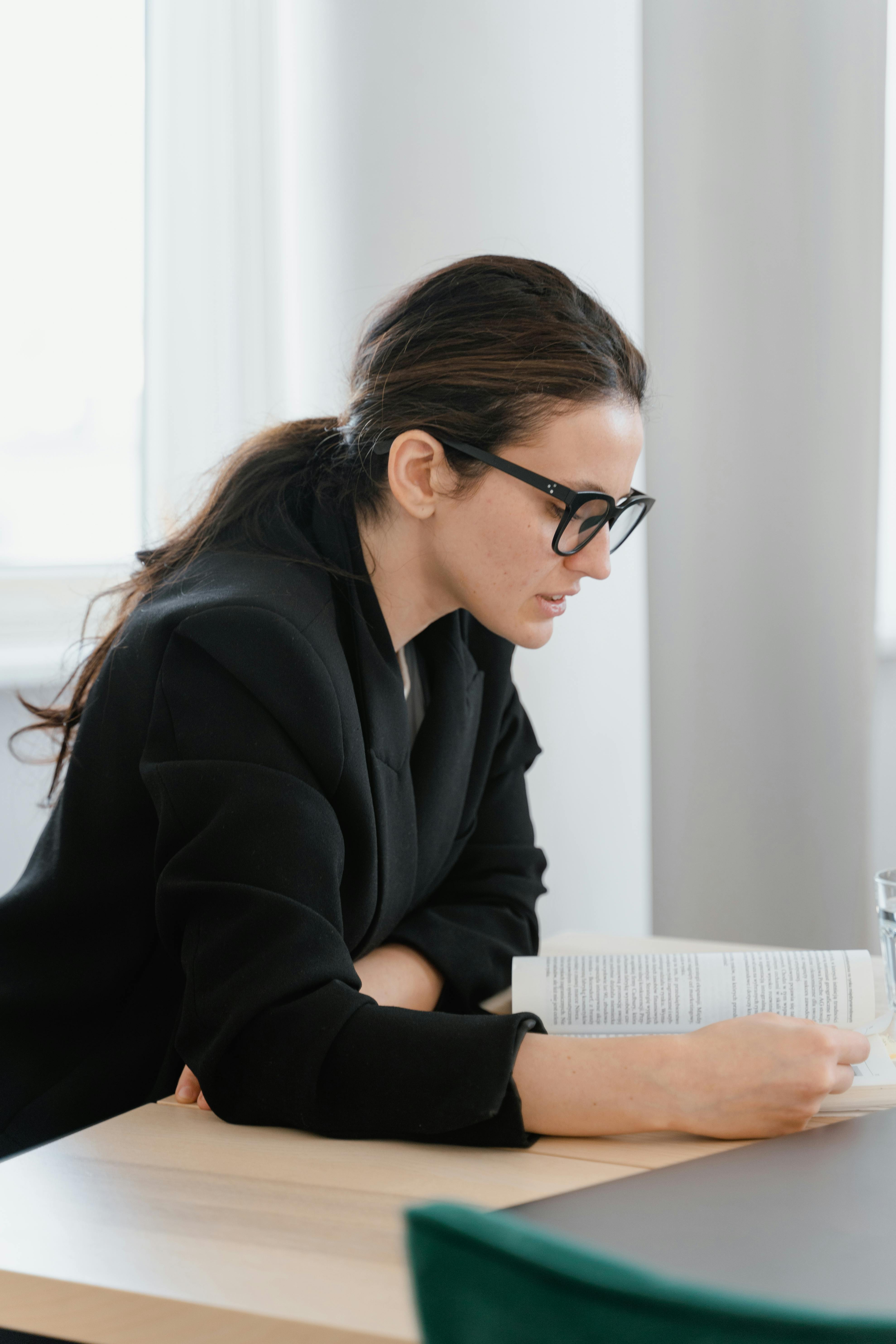 Side View of a Woman Reading a Book on a Table · Free Stock Photo