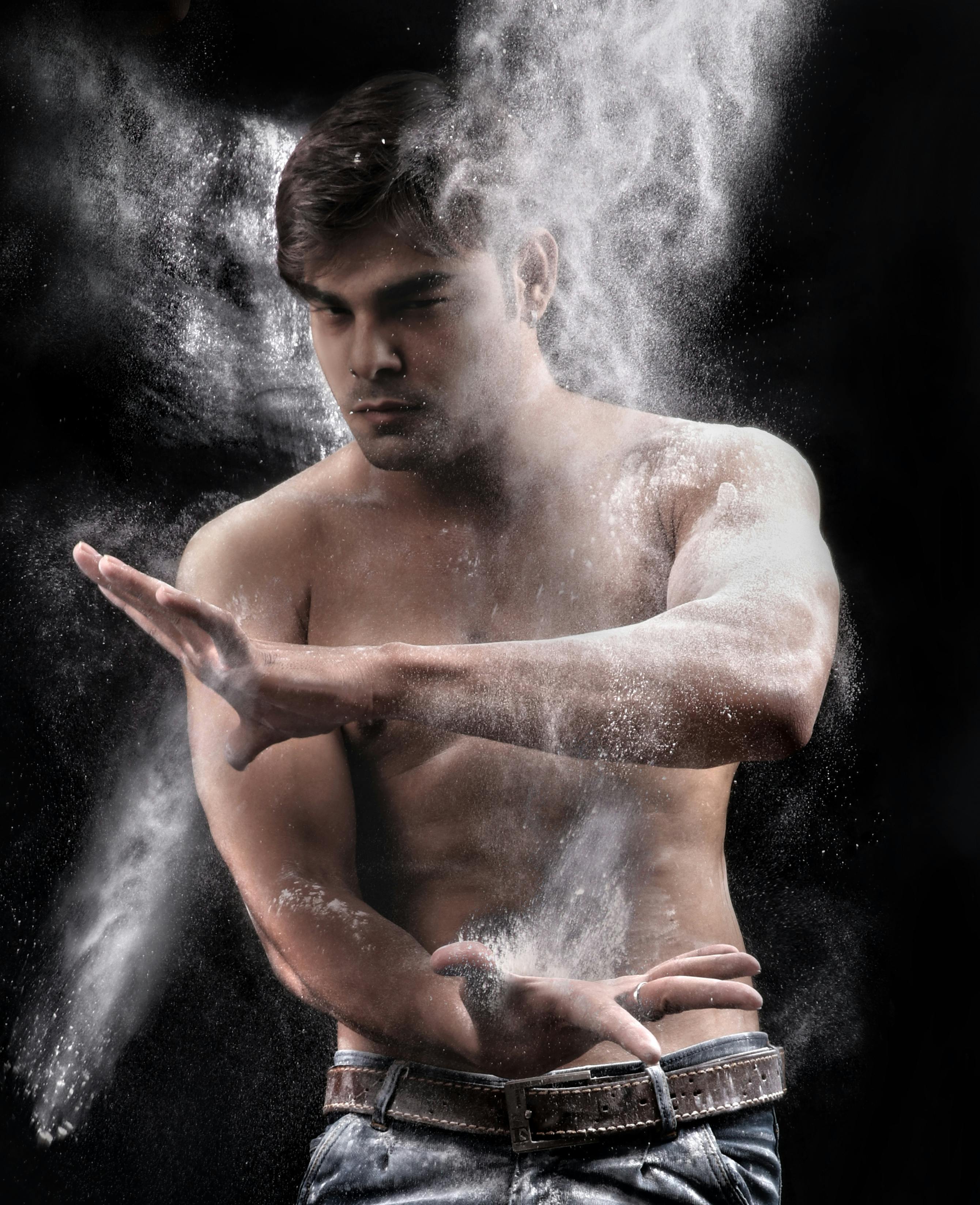 Photo of a Shirtless Model Throwing a Powder against Black Background ...