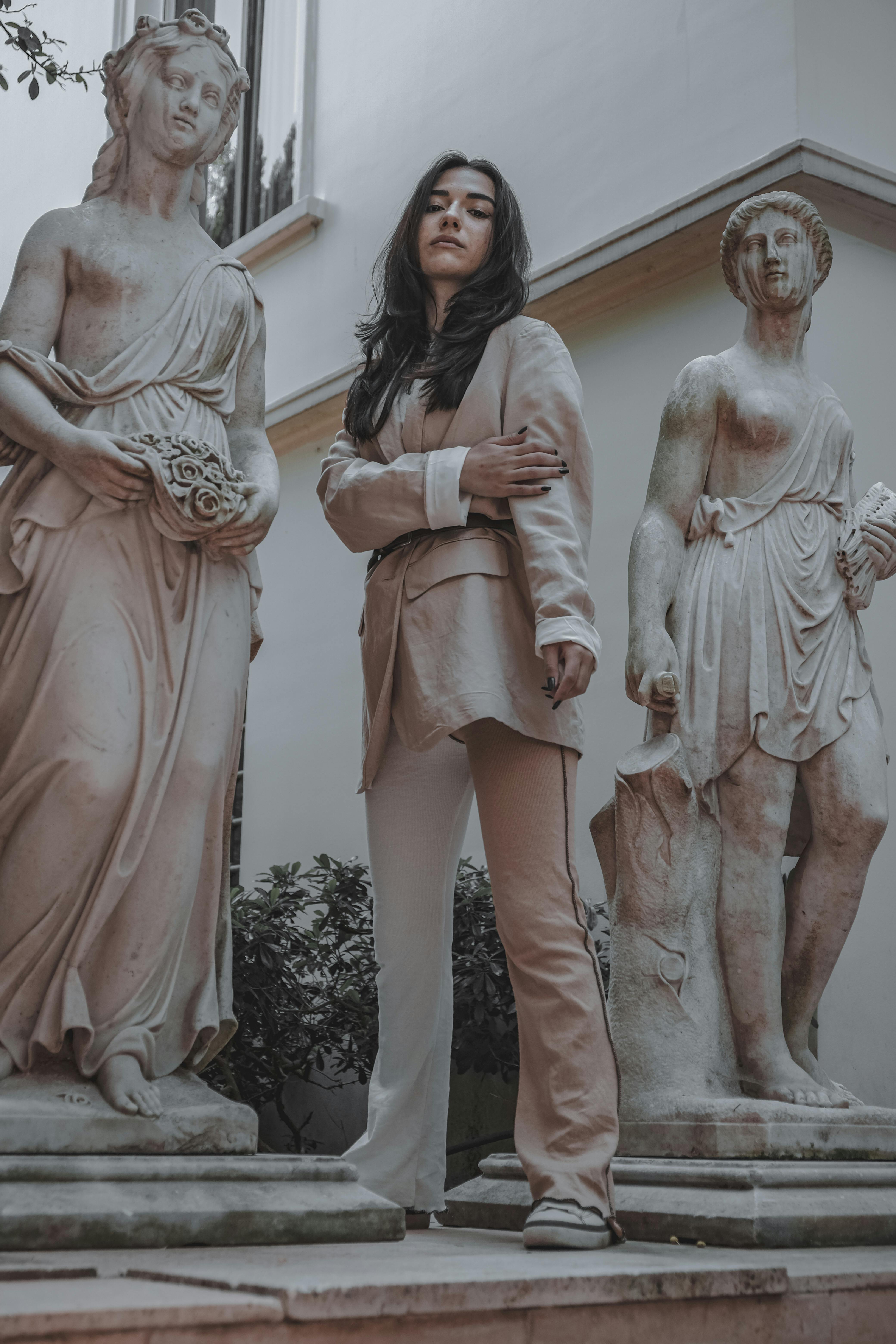 Beautiful Woman Standing Between Two Statues · Free Stock Photo