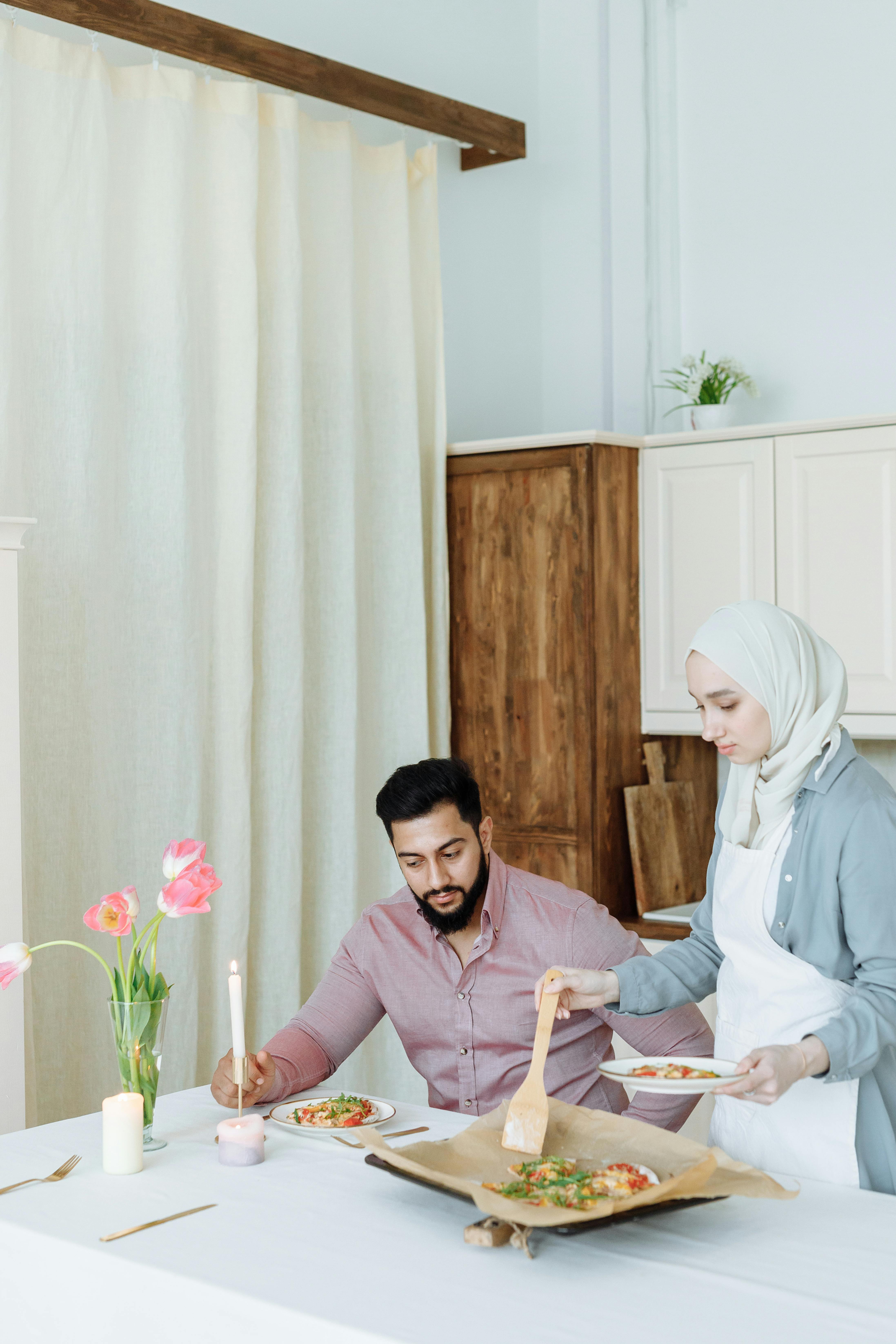 Man Sitting by the Table Beside a Woman Putting Food on Plate · Free ...