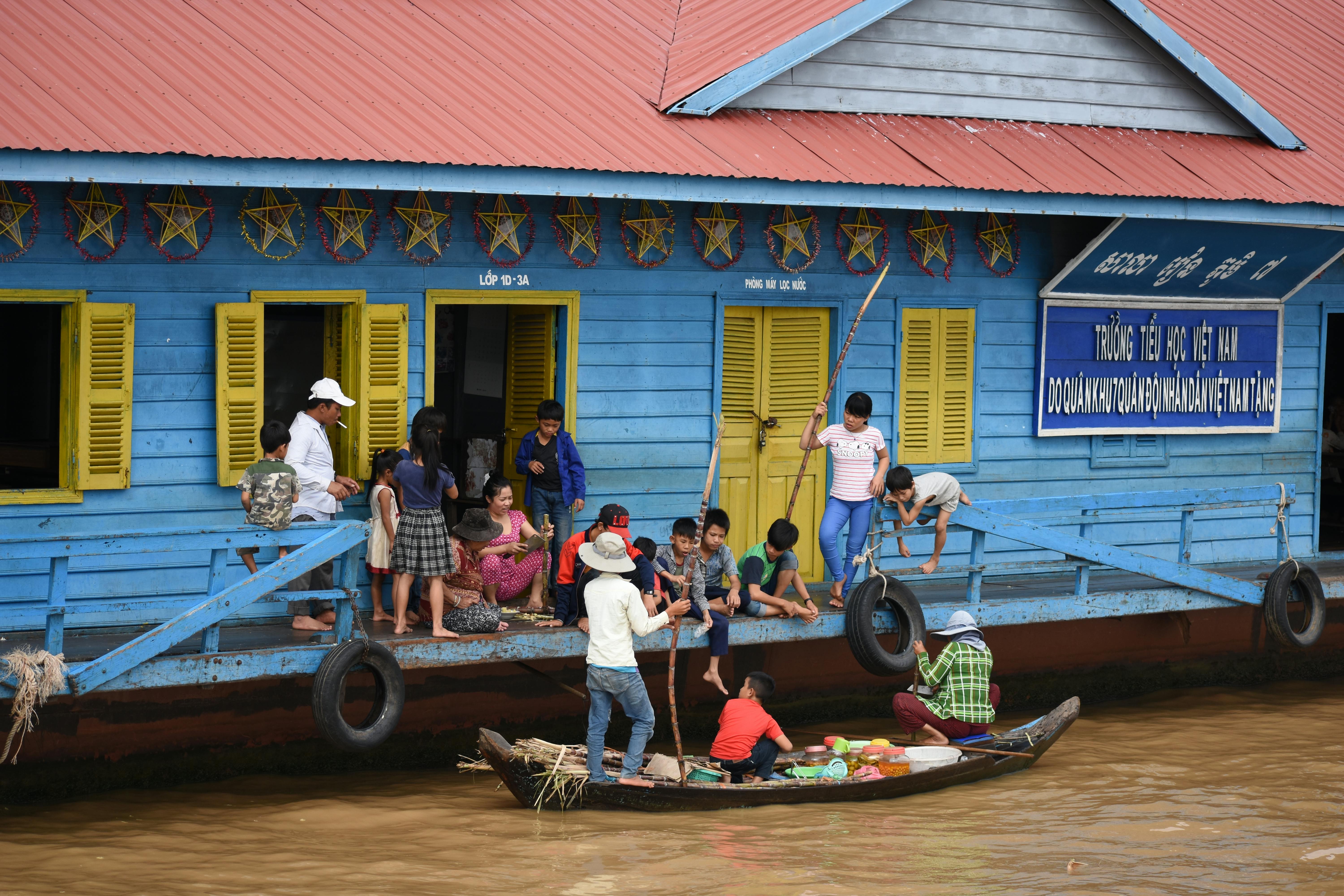 Local Boat Approaching Group of People in Harbor House · Free Stock Photo