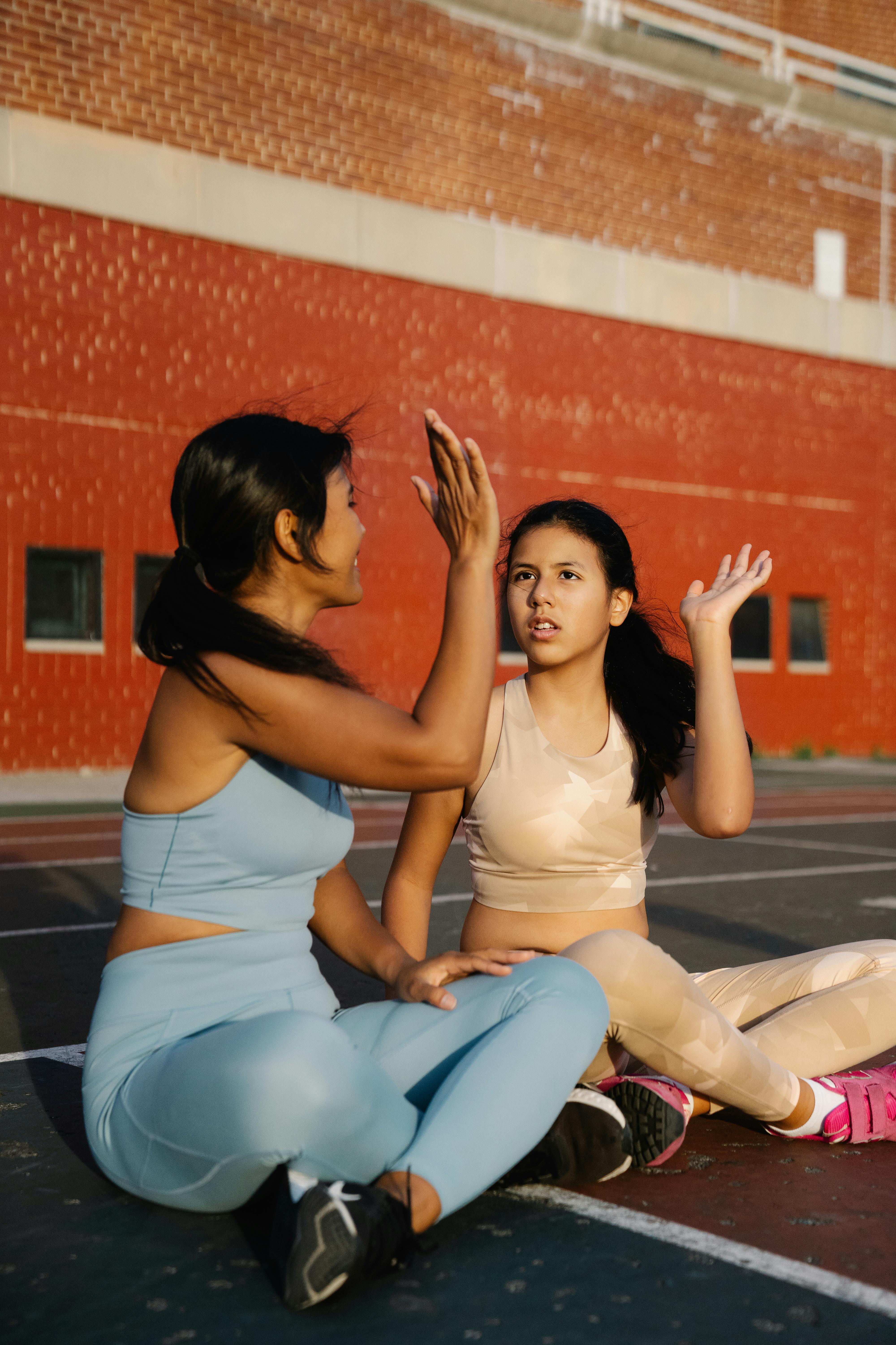 Women Sitting on a Pavement Doing a High Five · Free Stock Photo