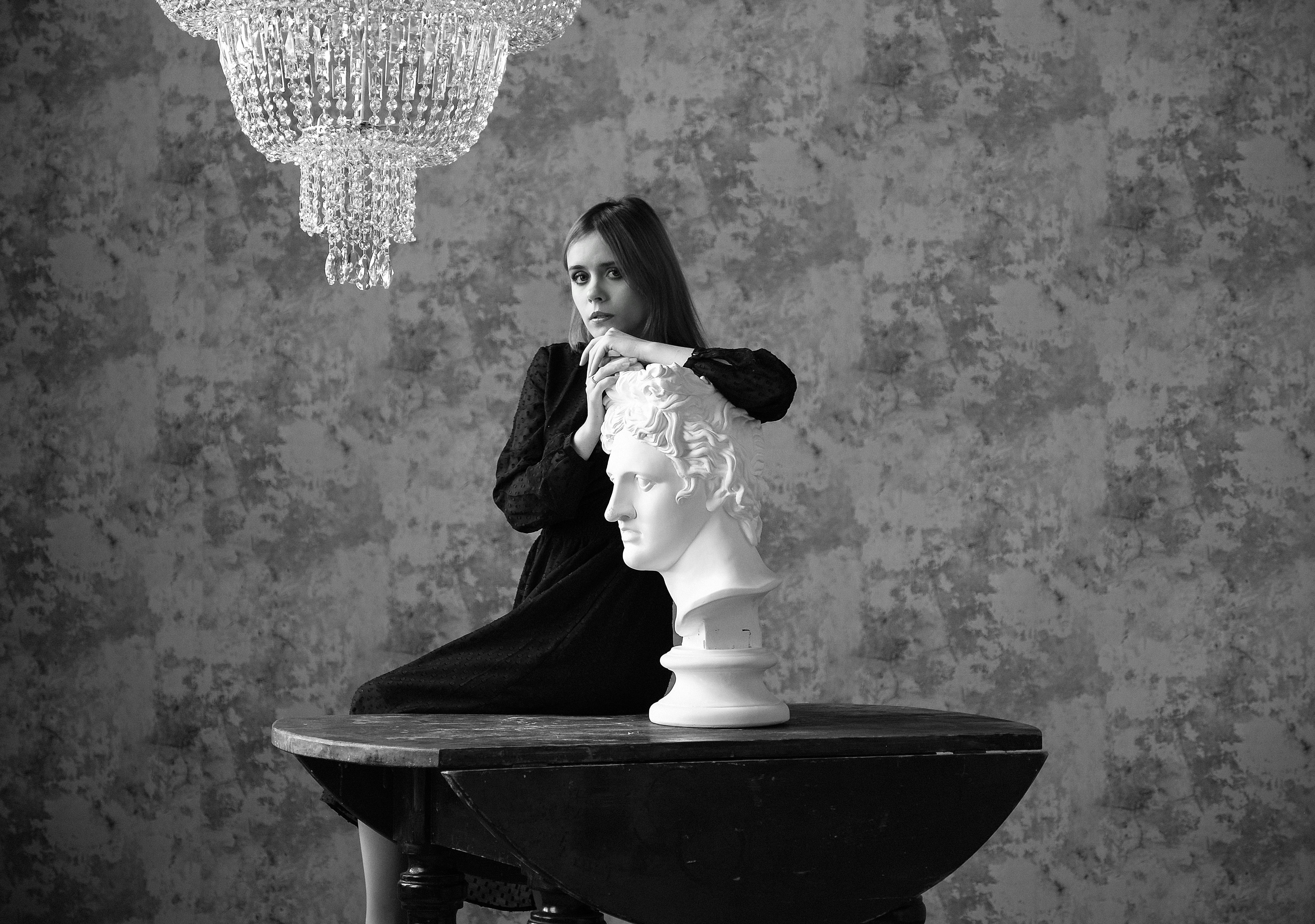 Elegant Woman Sitting on Table with Statue · Free Stock Photo