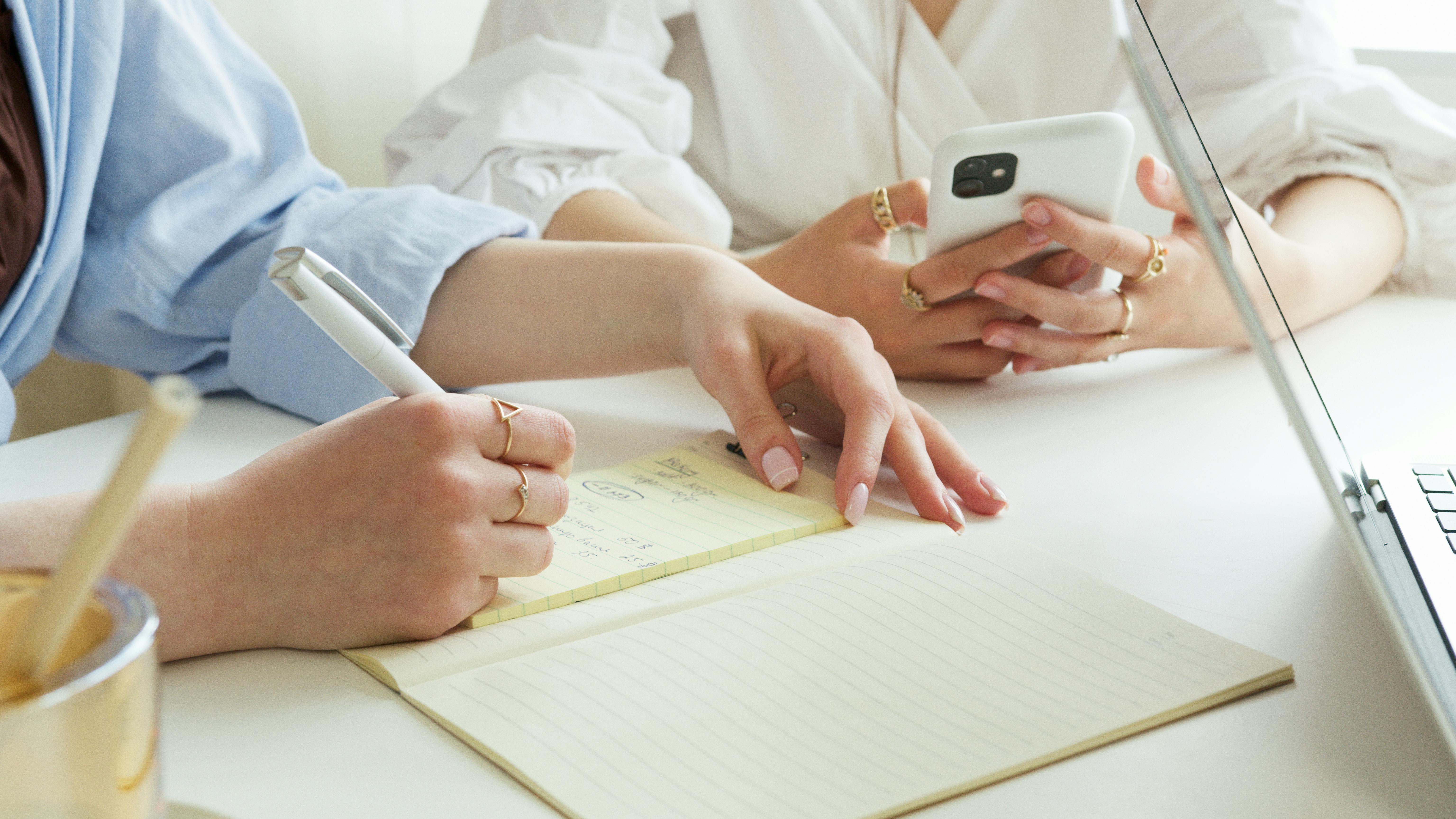Person in White Long Sleeves Writing on a Notepad · Free Stock Photo