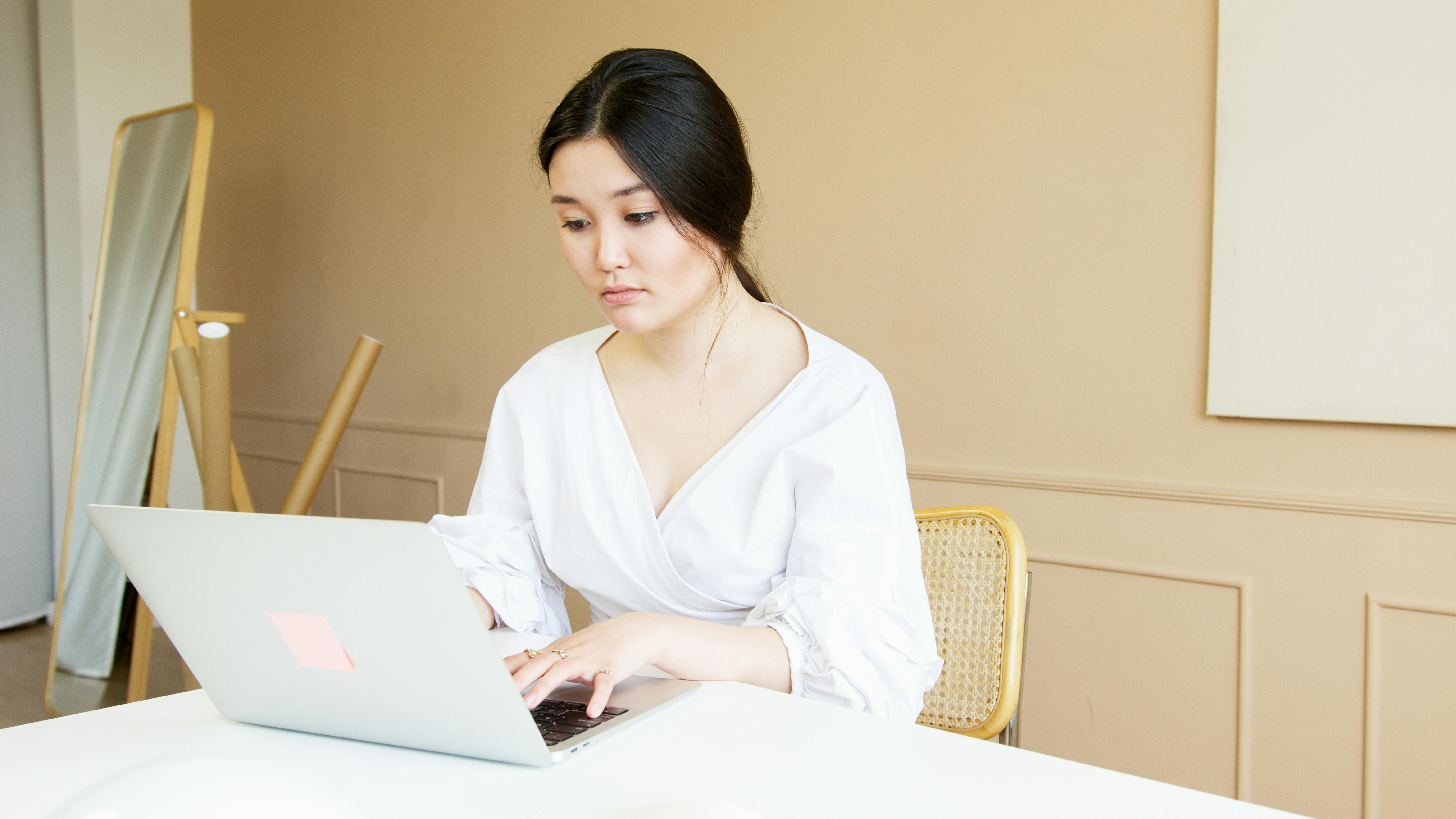 A Woman Typing while Looking at Boxes · Free Stock Photo
