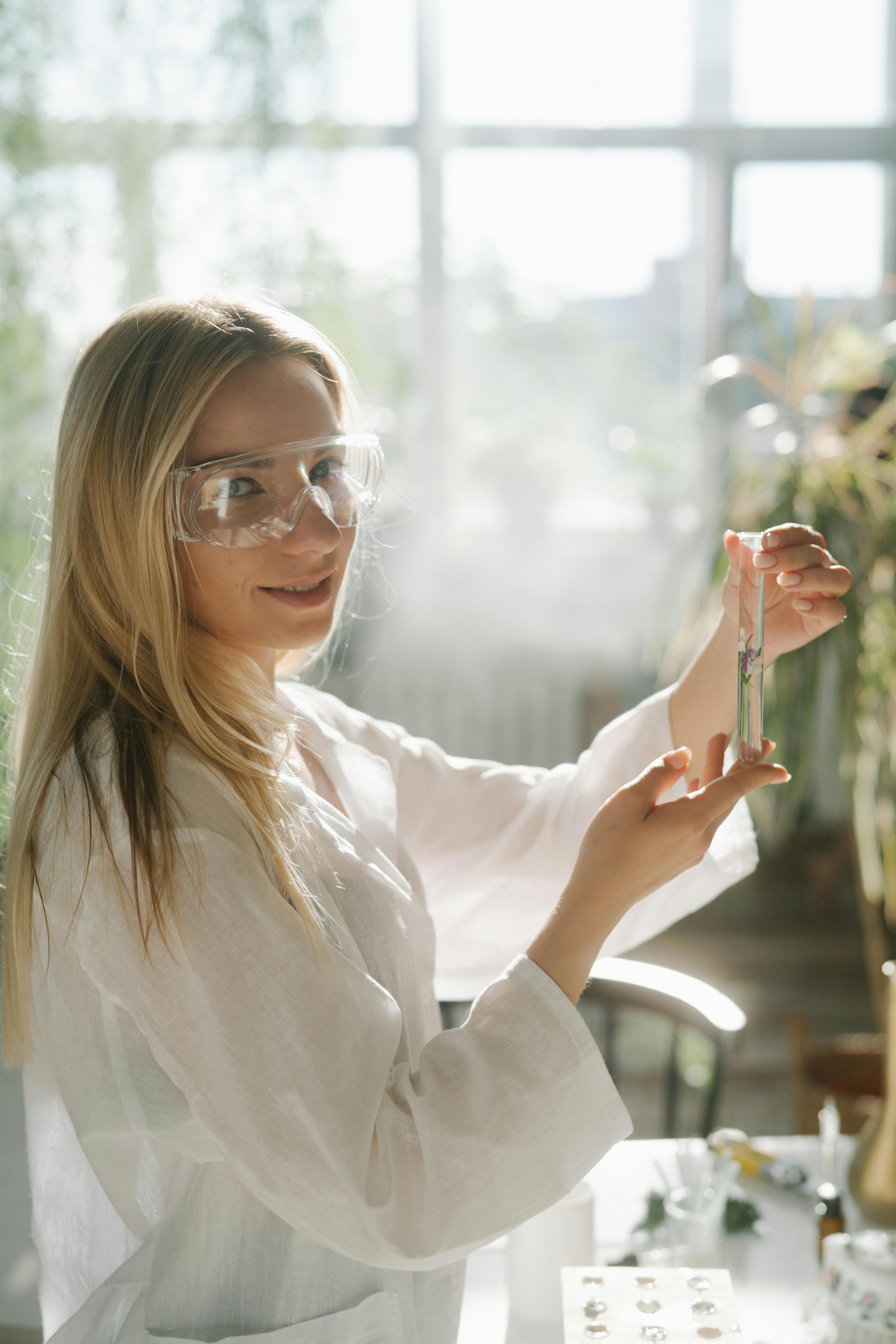 Blonde Woman in White Lab Gown Wearing Protective Googles while Holding ...