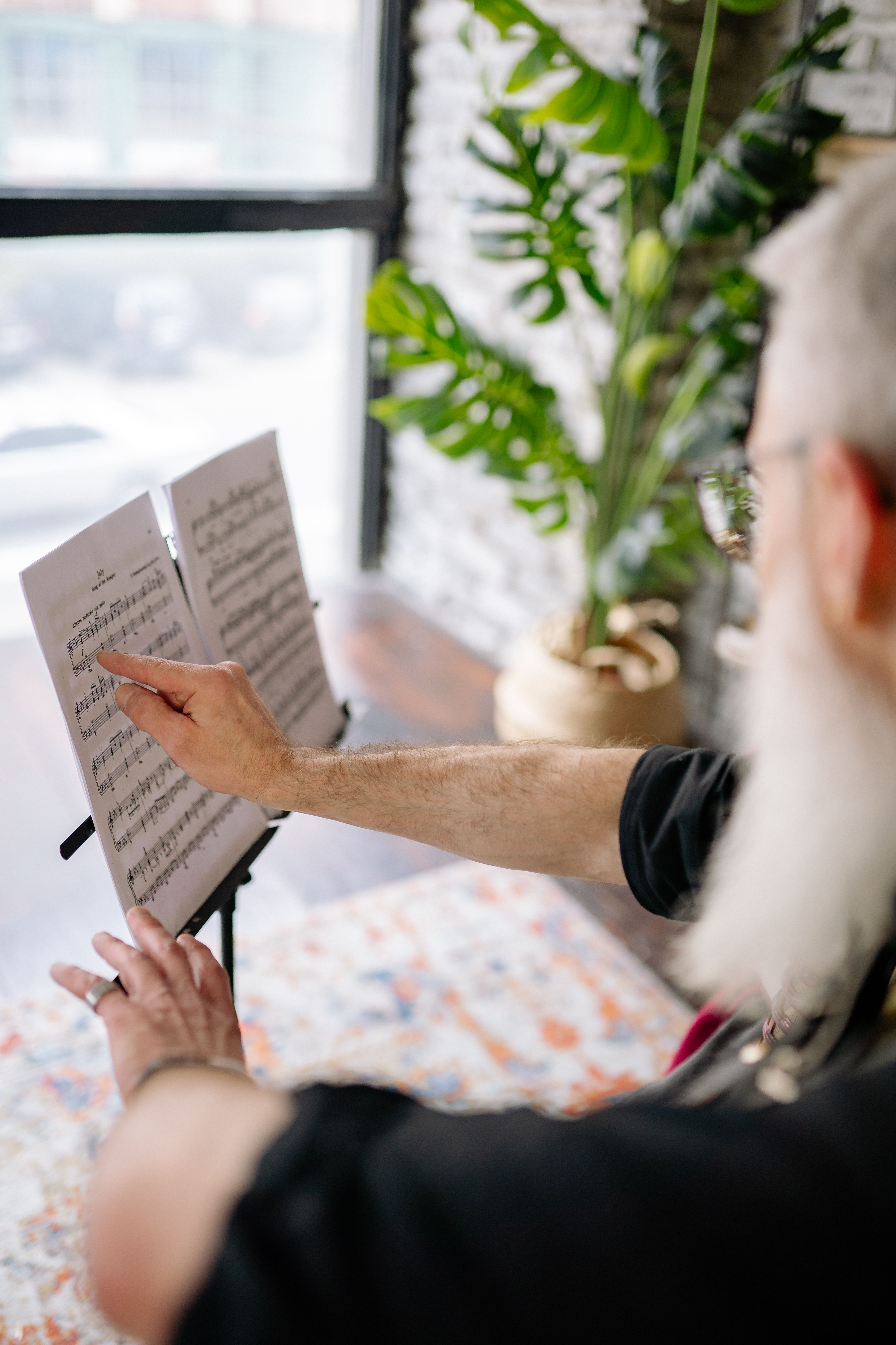 Elderly Man Pointing at Notes on a Music Sheet · Free Stock Photo