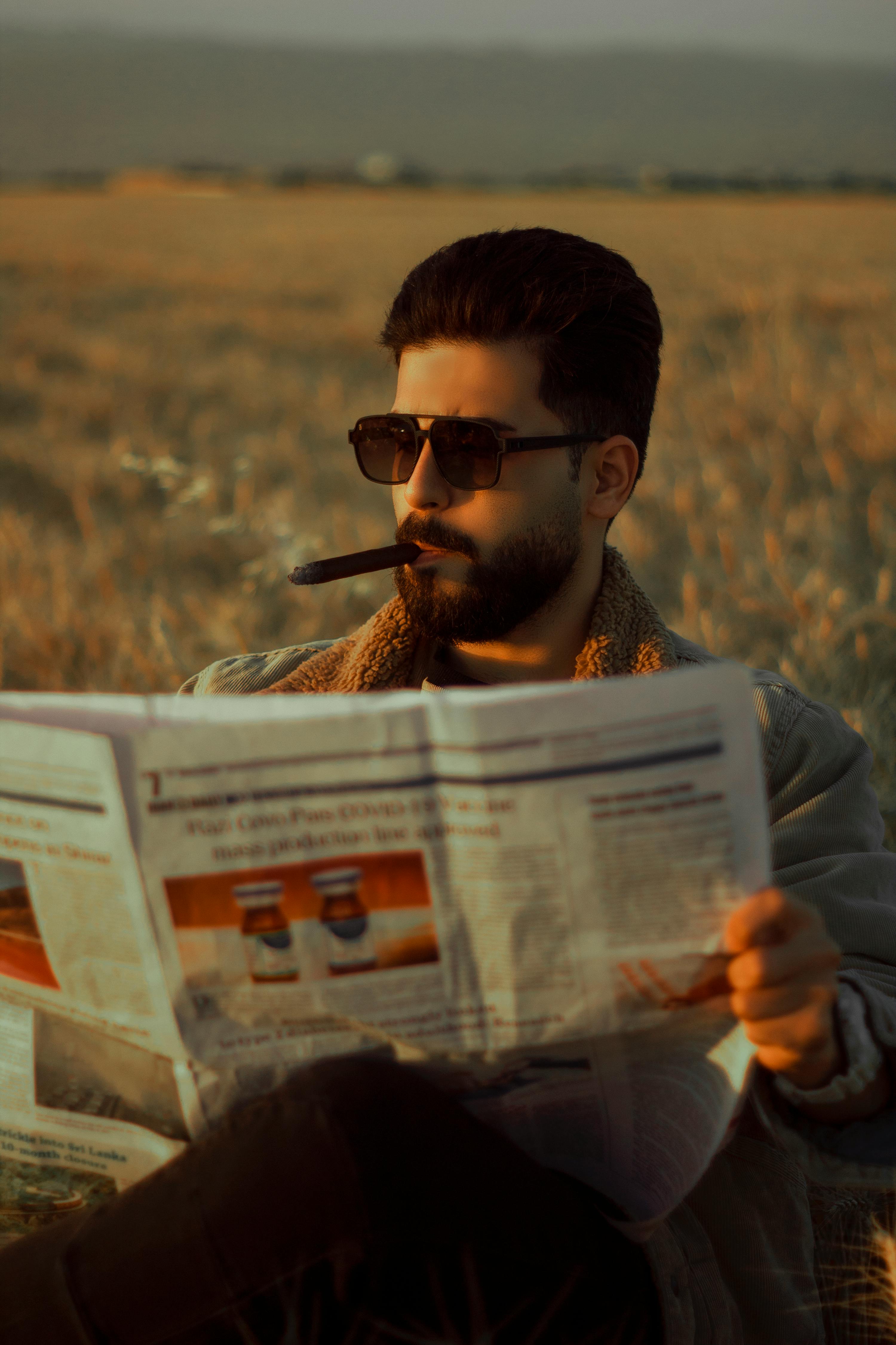 Man Reading Newspaper on Chair on Dirt Road · Free Stock Photo