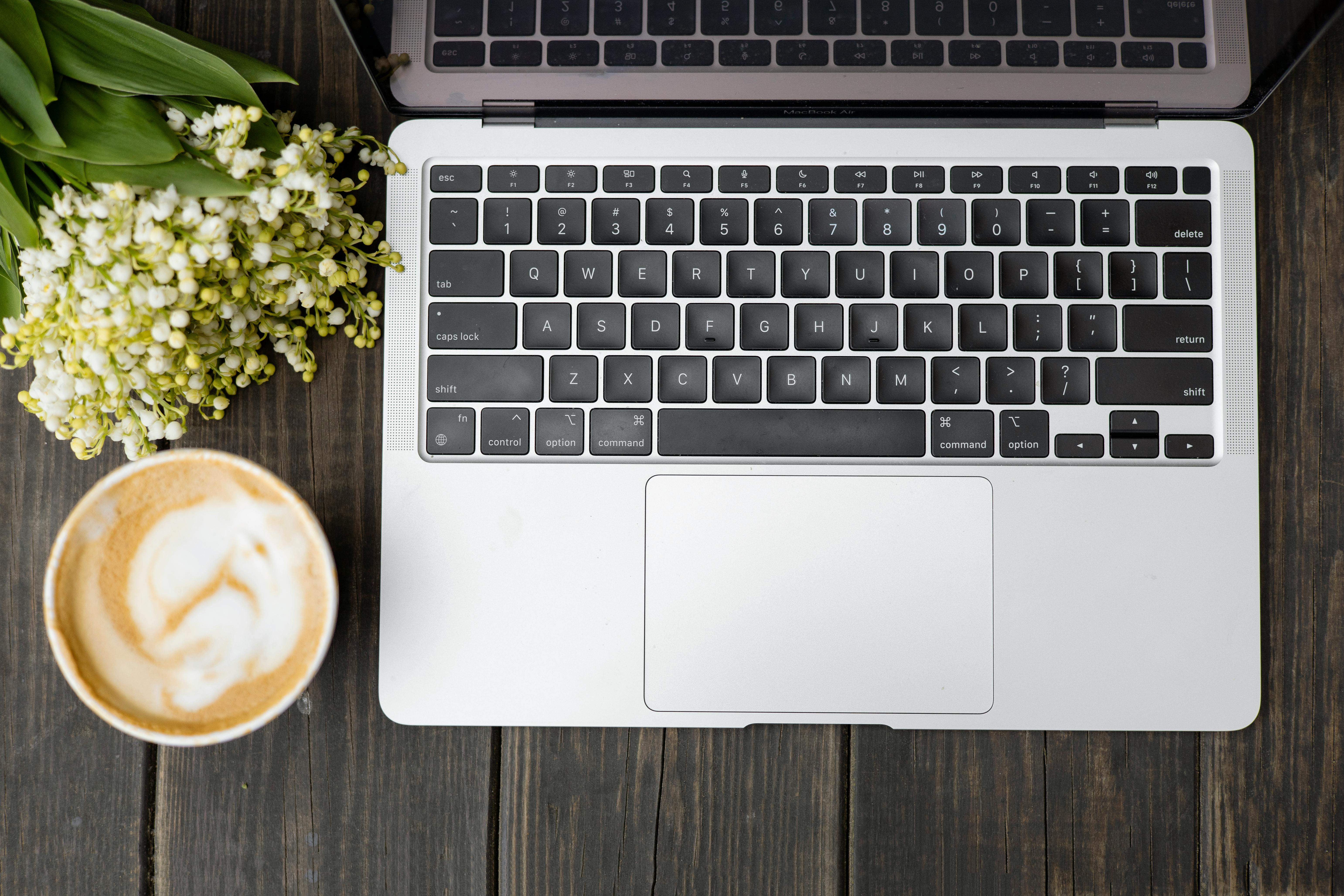 A Cup of Coffee Beside a Laptop on a Wooden Surface · Free Stock Photo