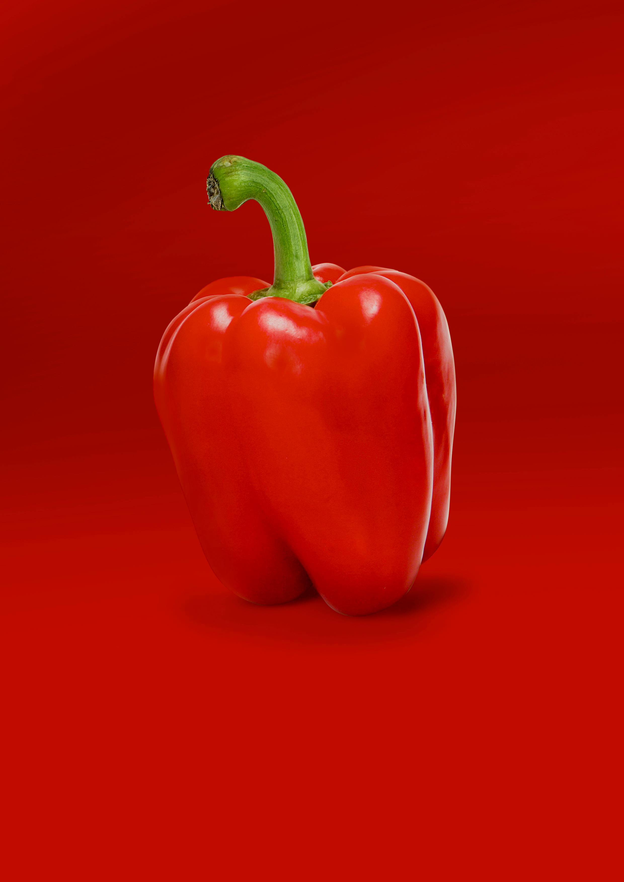 Close-Up View Red Bell Pepper on Red Surface · Free Stock Photo