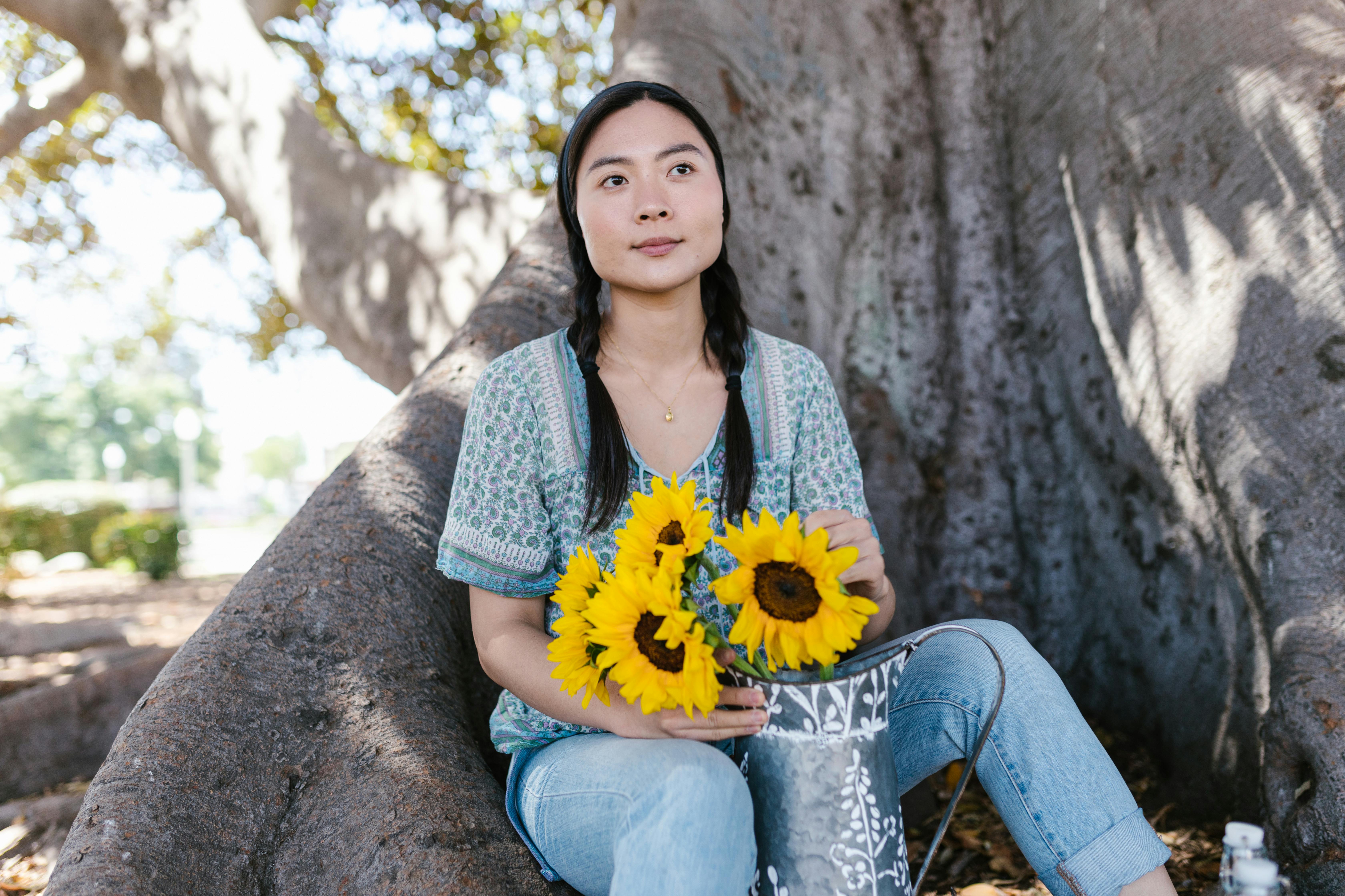 A Young Woman Sitting by a Tree Trunk · Free Stock Photo