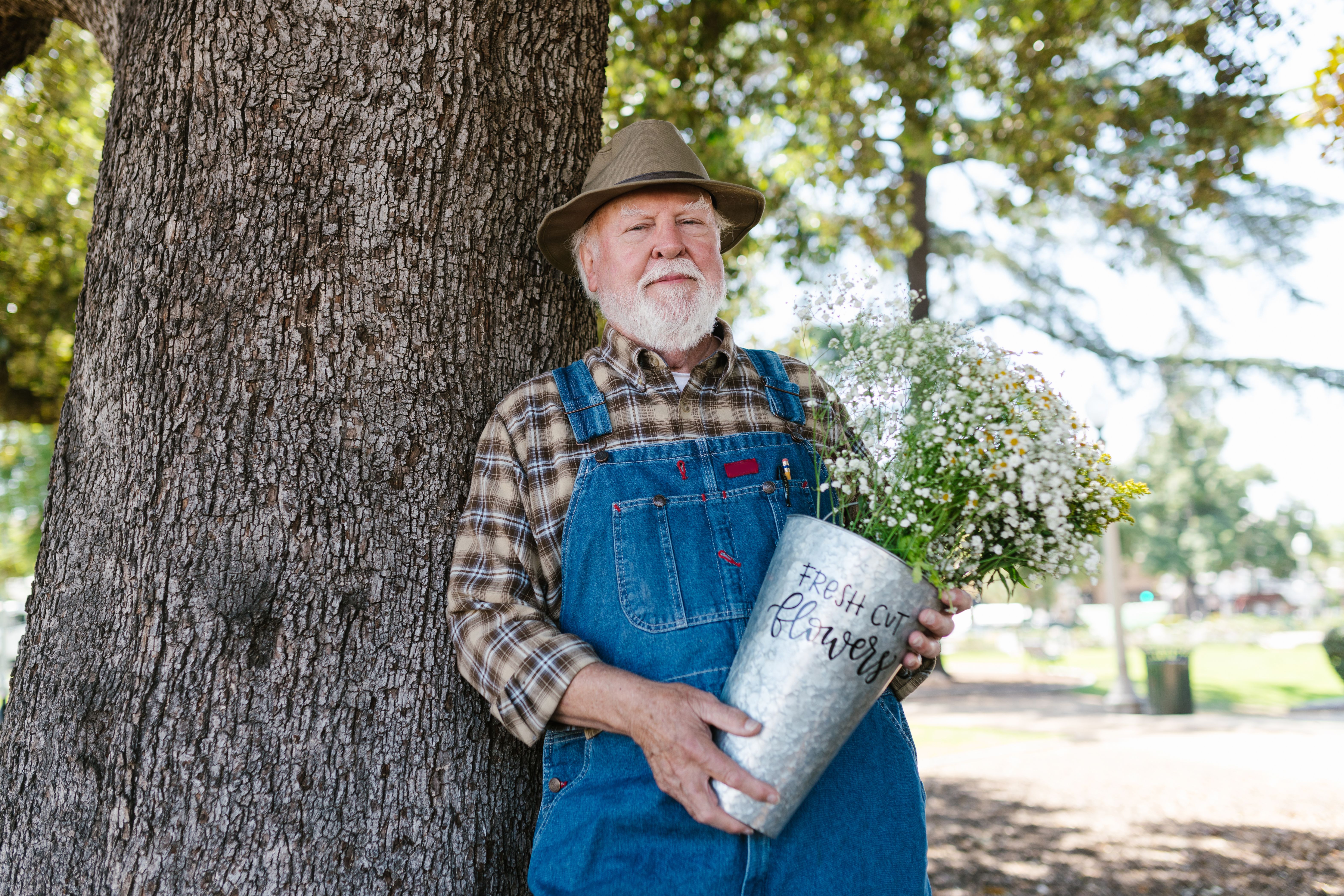 An Elderly Man Leaning on the Tree Trunk while Holding a Stainless Pot ...